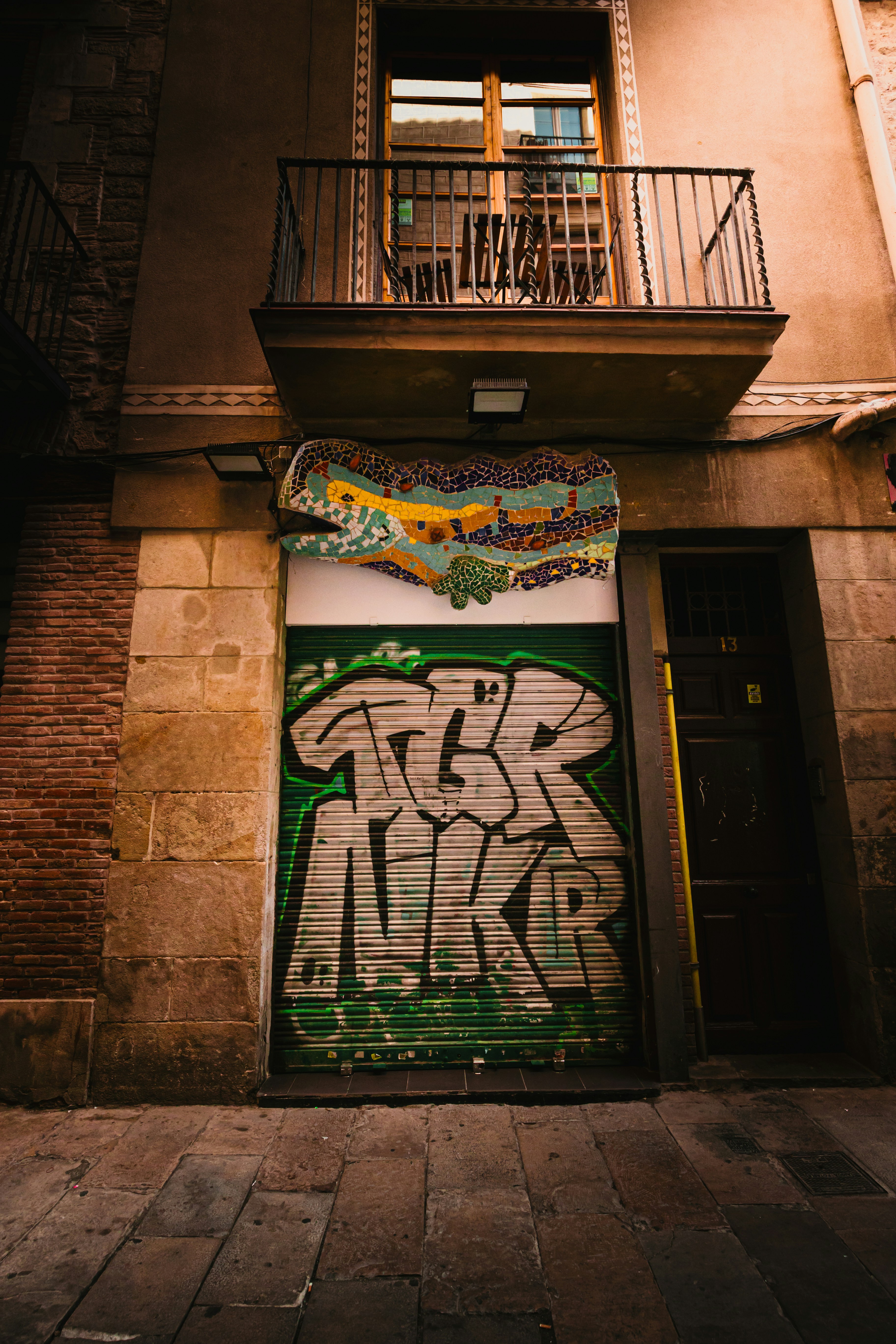Graffiti Gate: A Closed Shop Beneath a Balcony