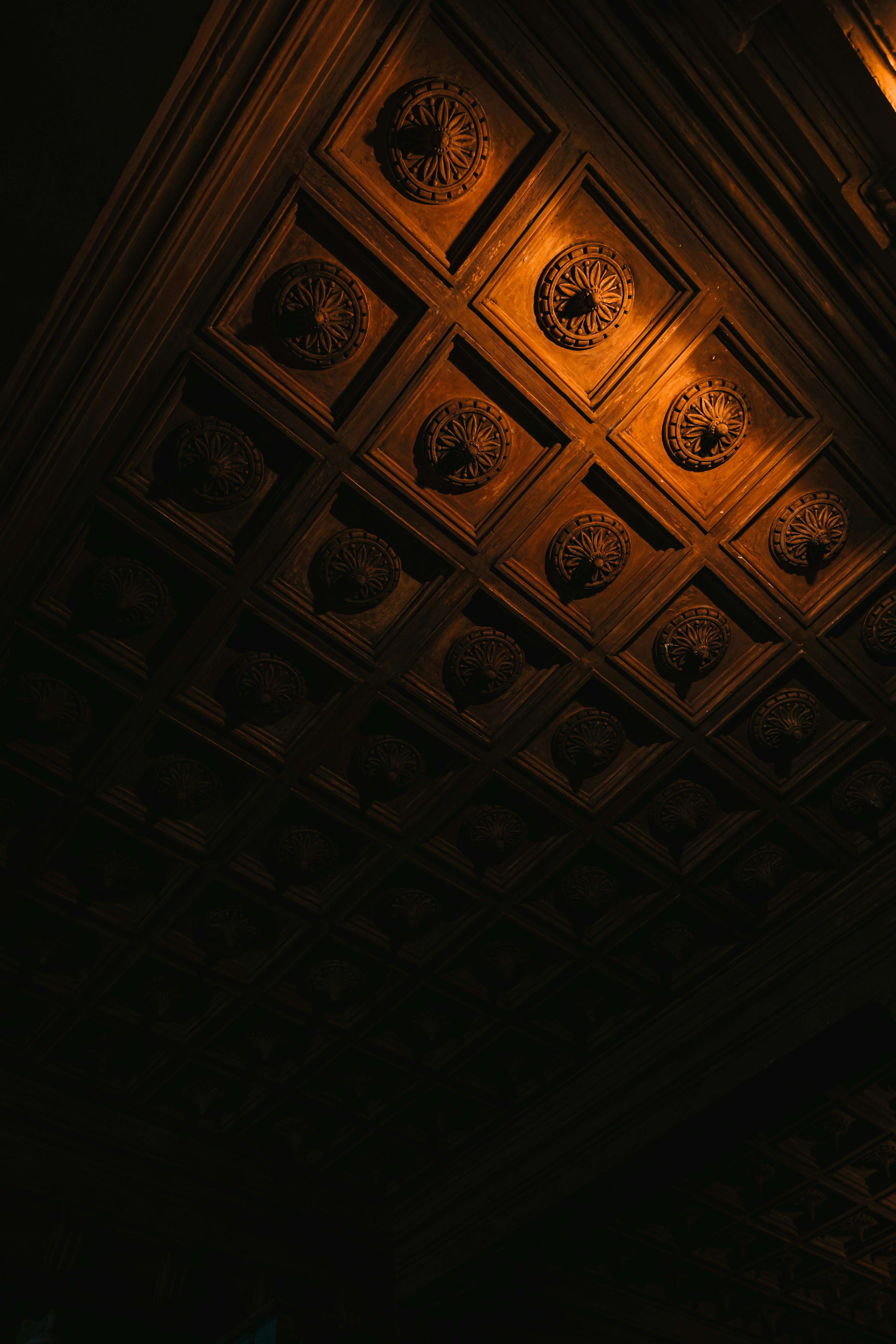 Dim golden tessellations: ornate ceiling tiles glow under corner light