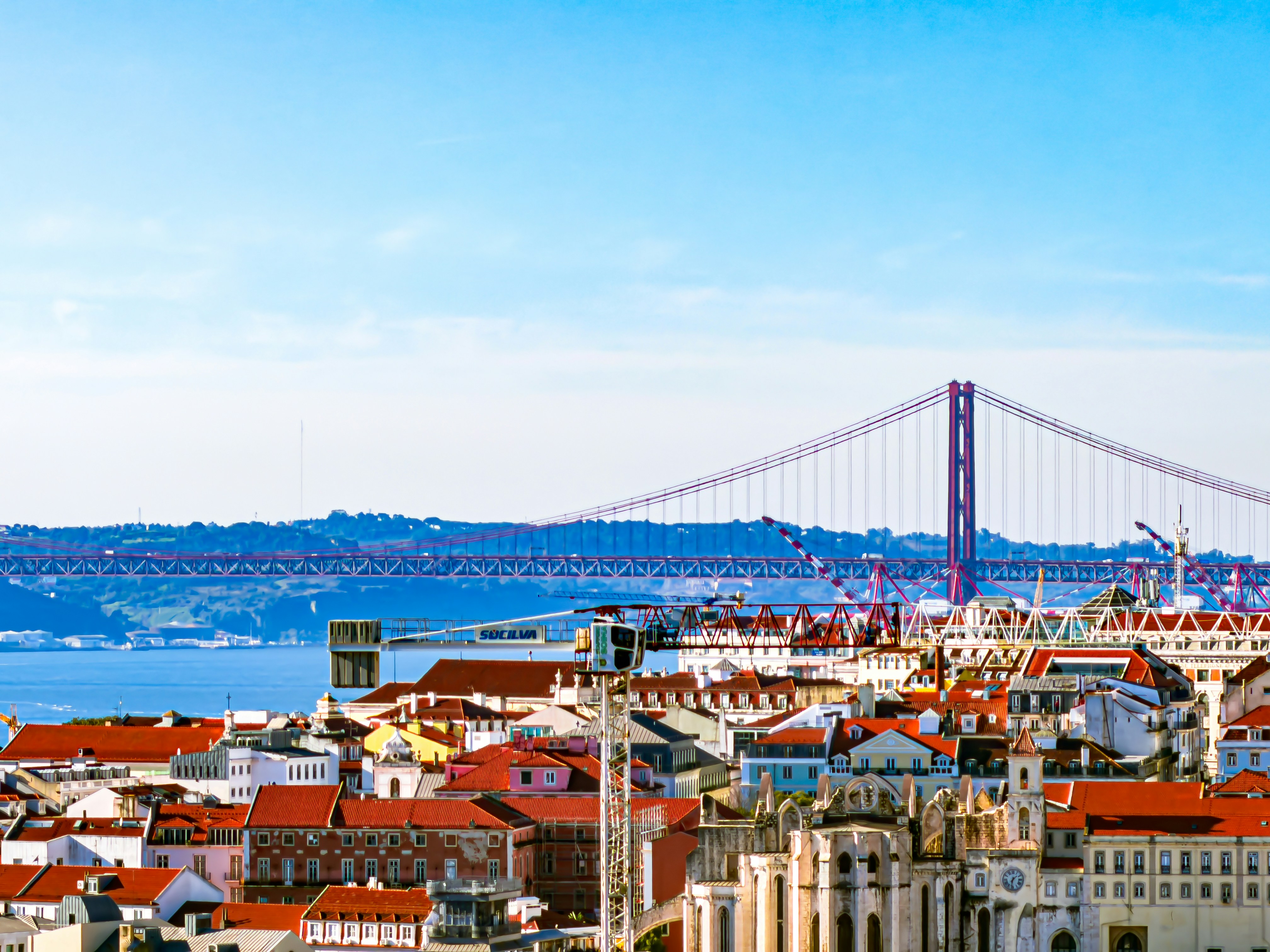 Bridge, rooftops, and distant horizon: A sunlit harbor cityscape