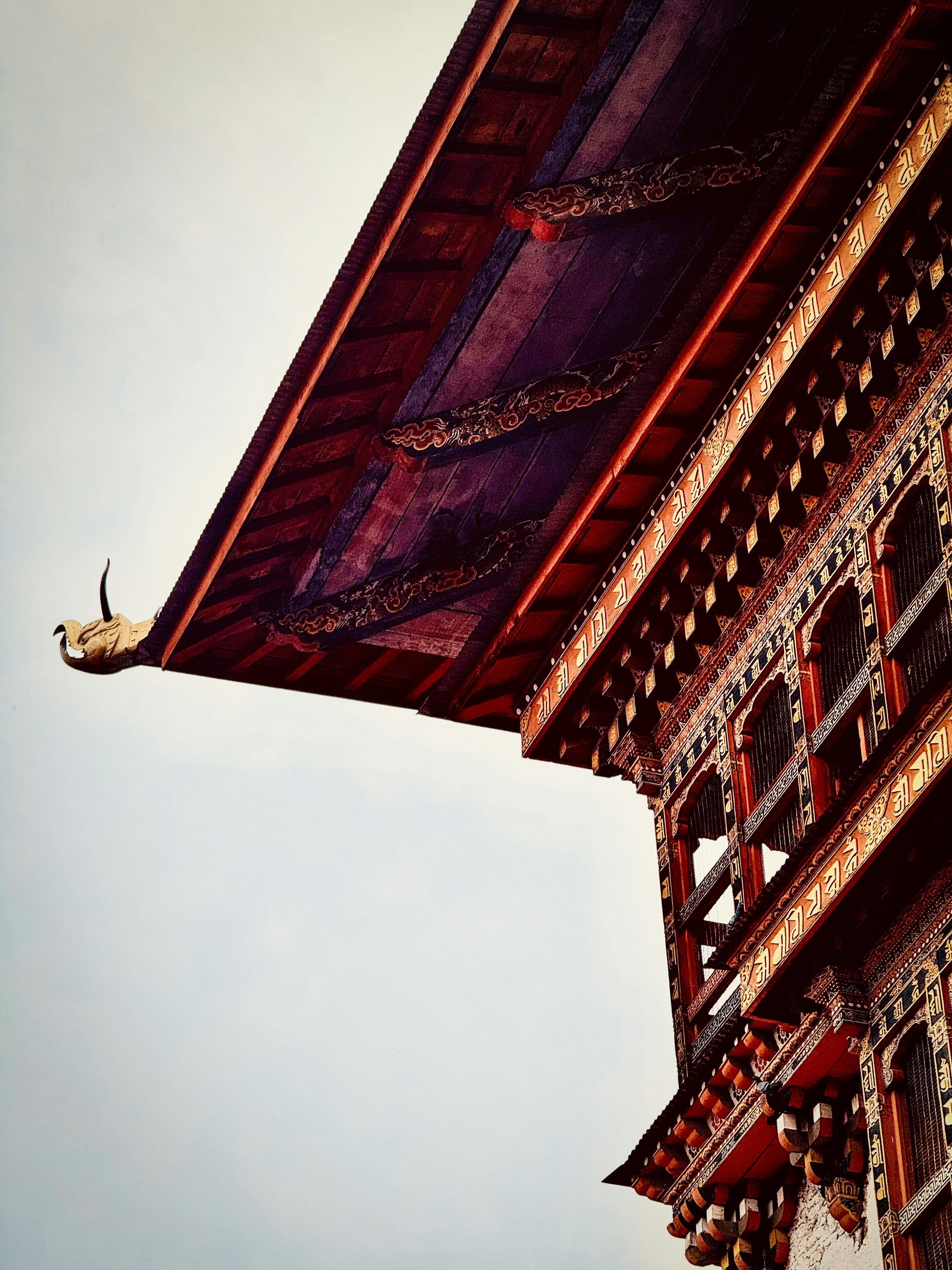 Eaves of History: Ornate Roofline Reaches Toward a Bleached Sky