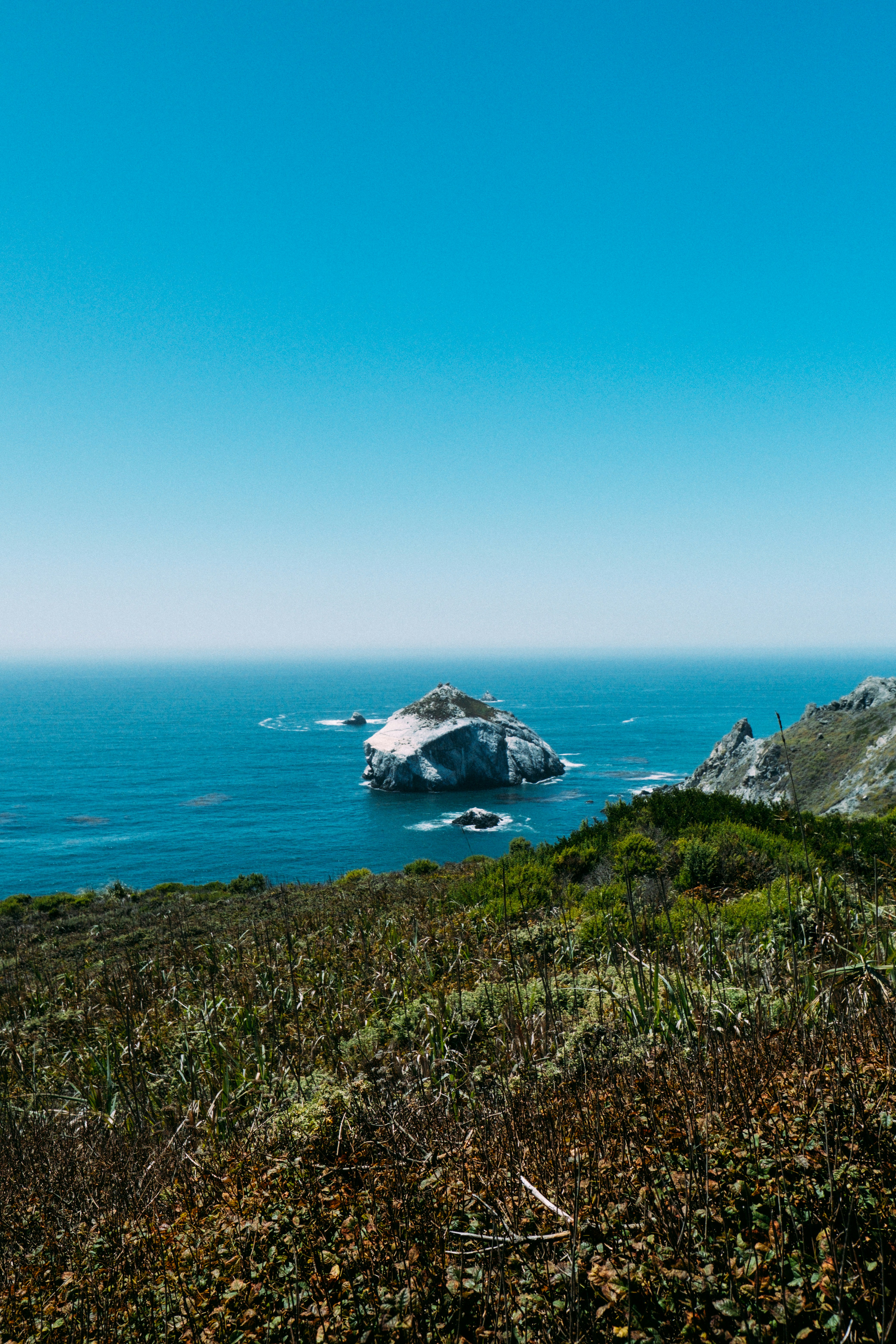 Coastal Outcrop: A Snow-Capped Rock Watches Over the Blue Expanse