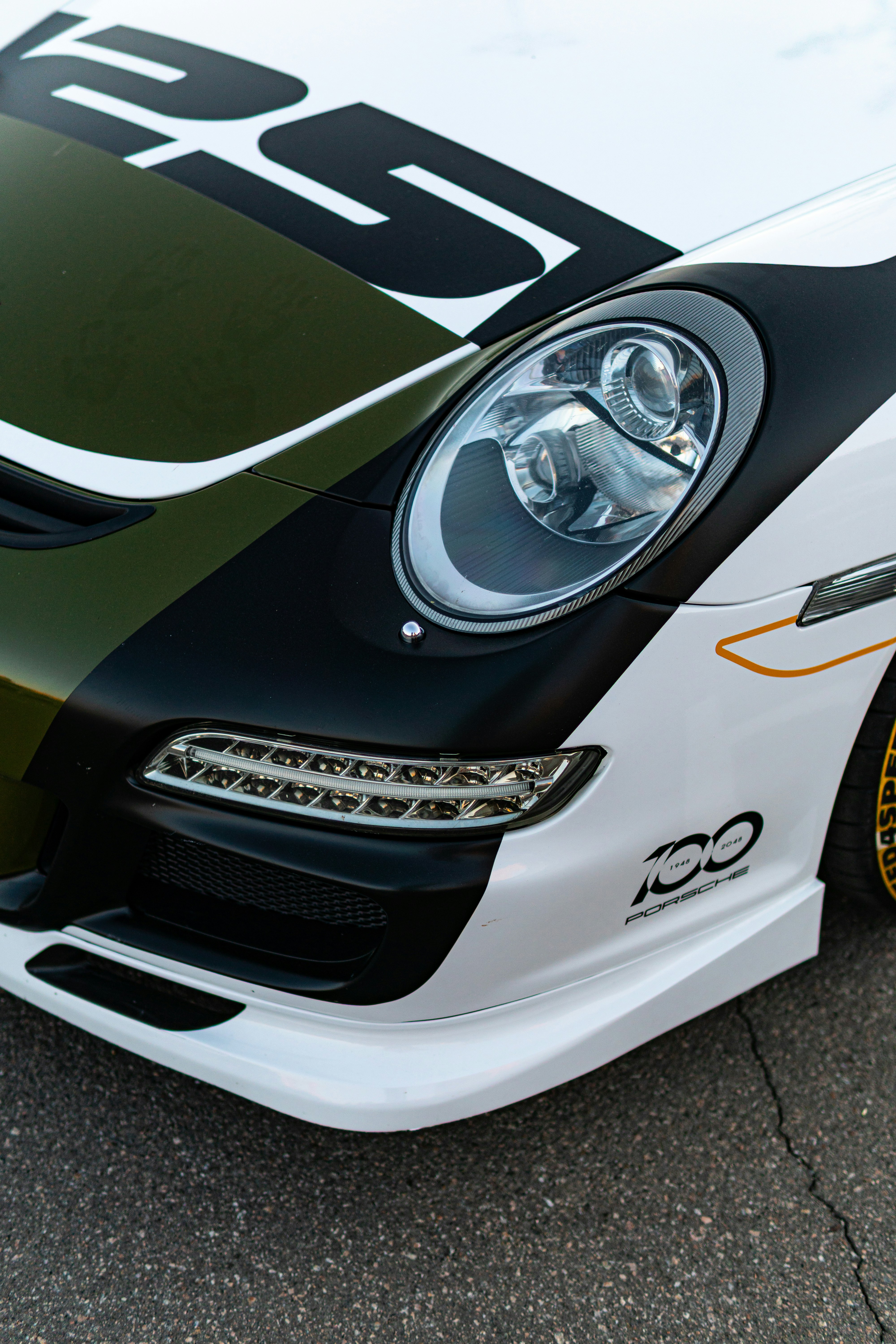 Close-up of a race-style Porsche front: bold headlamp and aero details