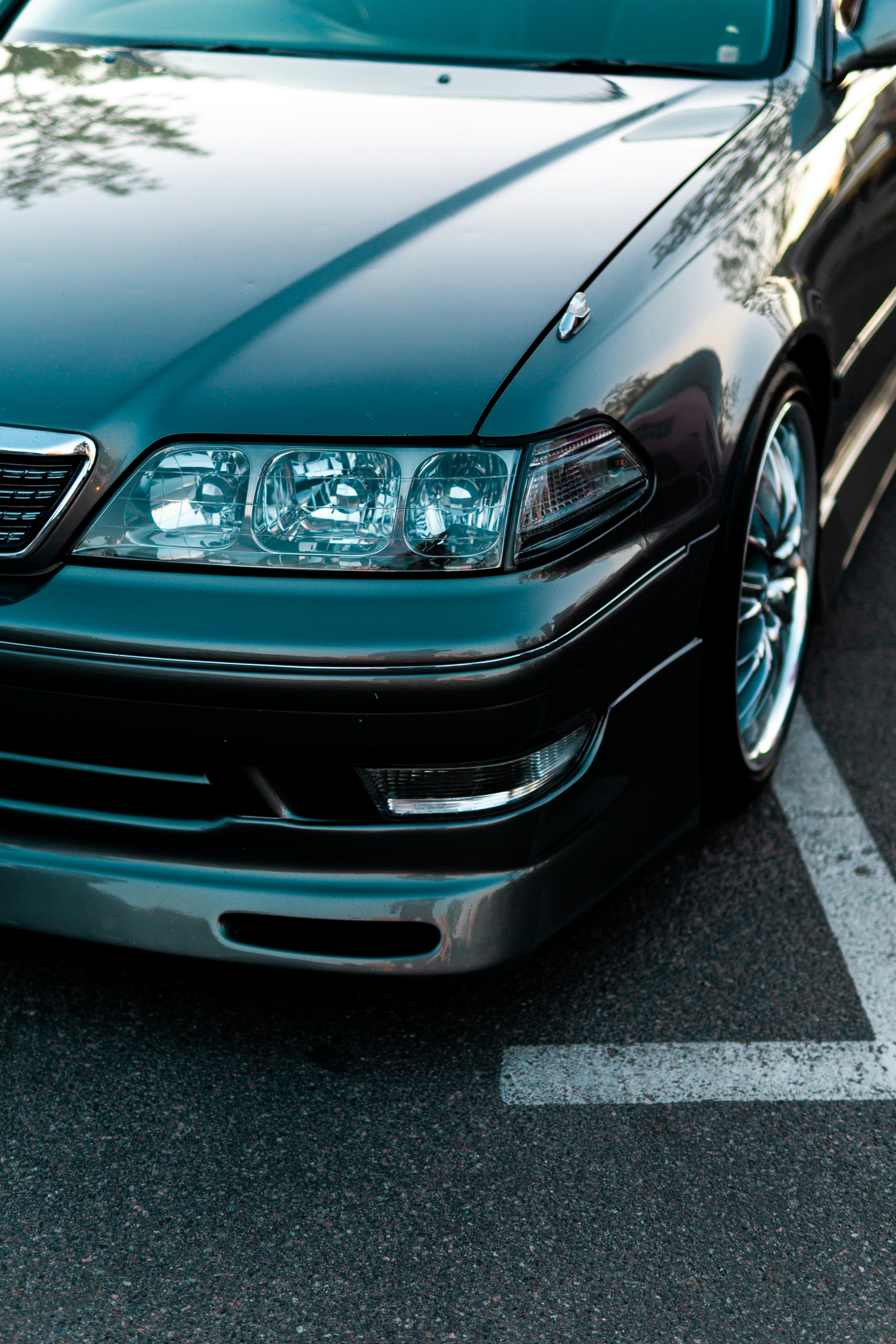 Shiny teal coupe at an angled curb showpiece