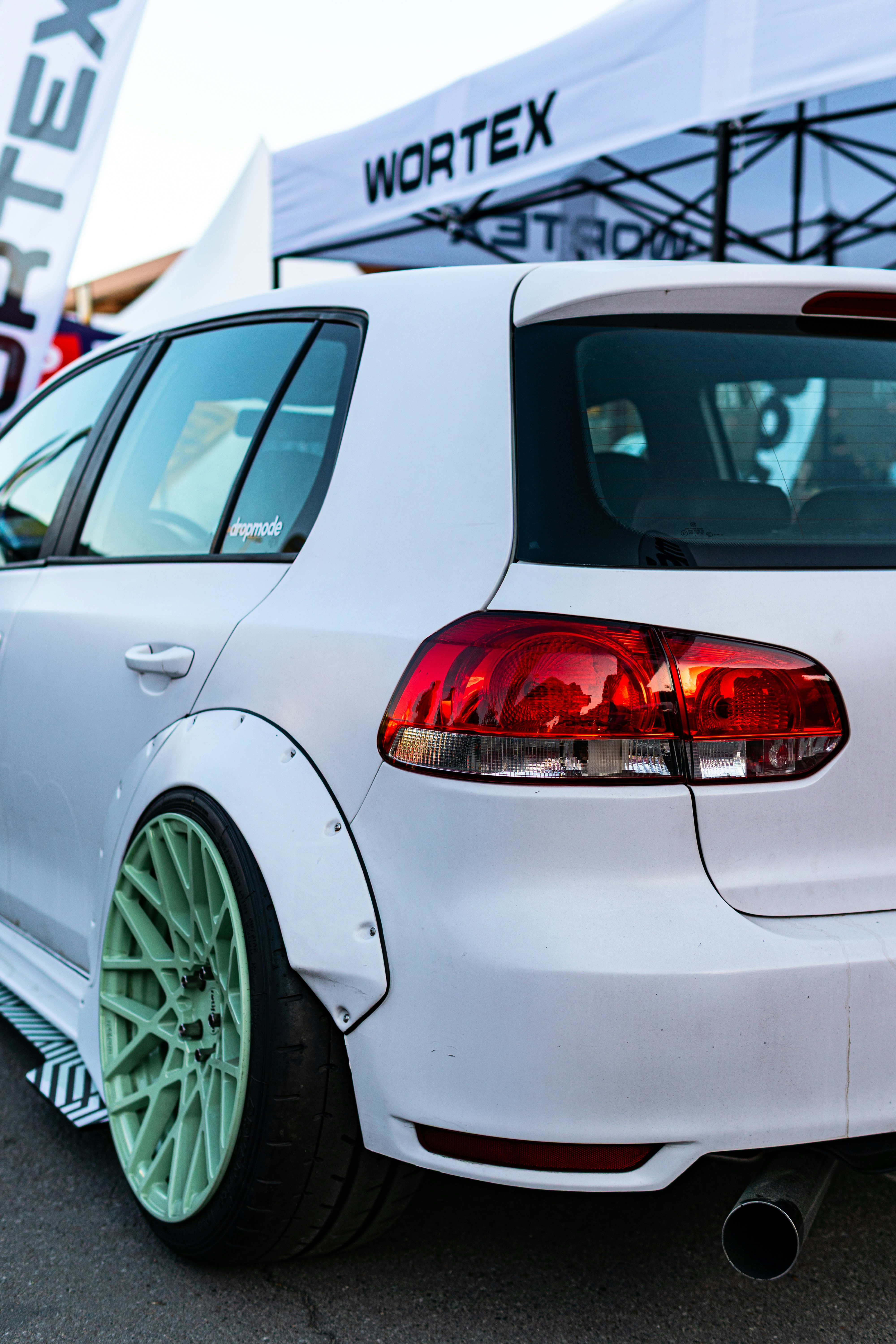 Minted Mischief: A White Hatchback with Mint Green Rims at the Show