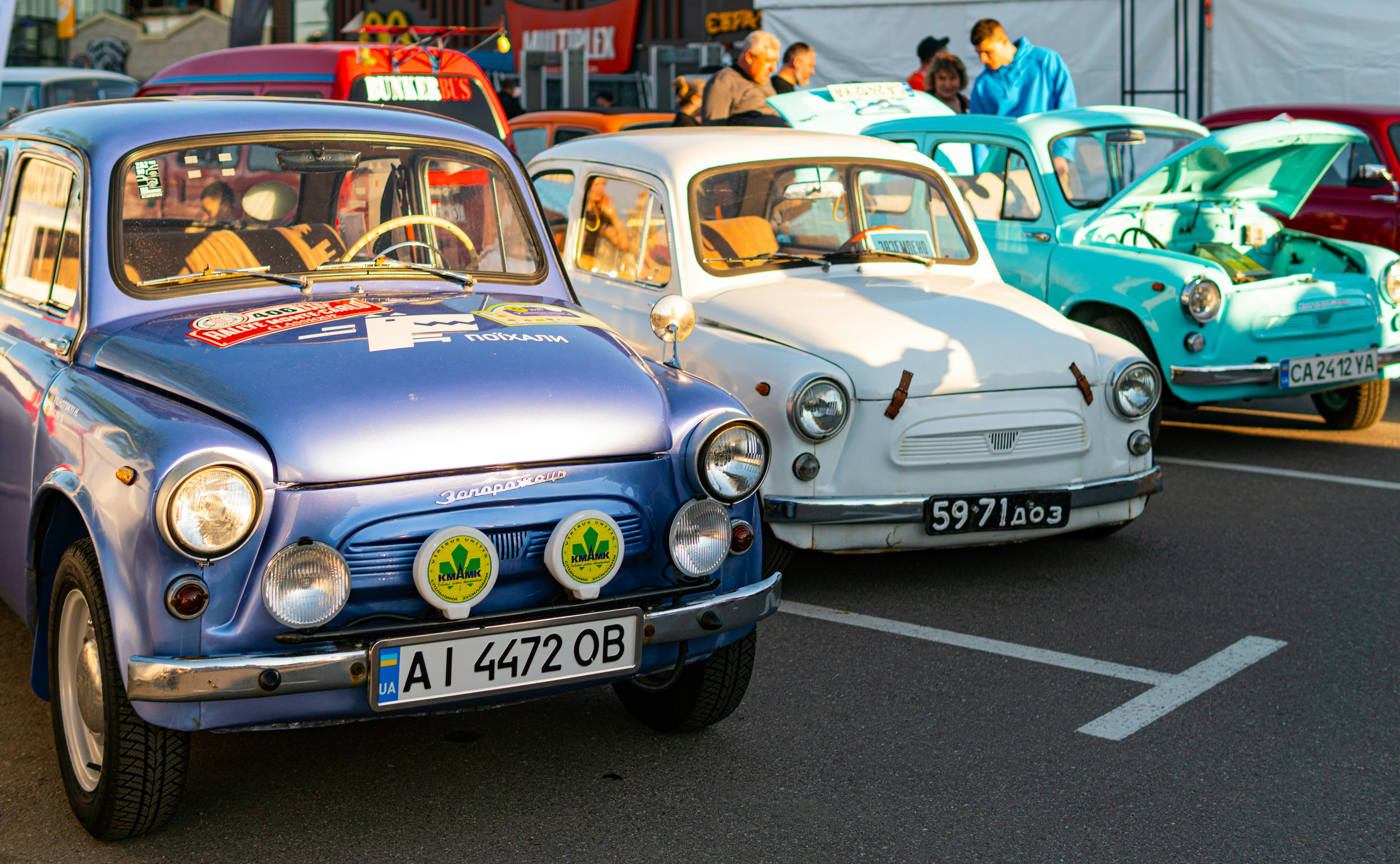 Blue vintage car leads a row of colorful classic autos at a car show