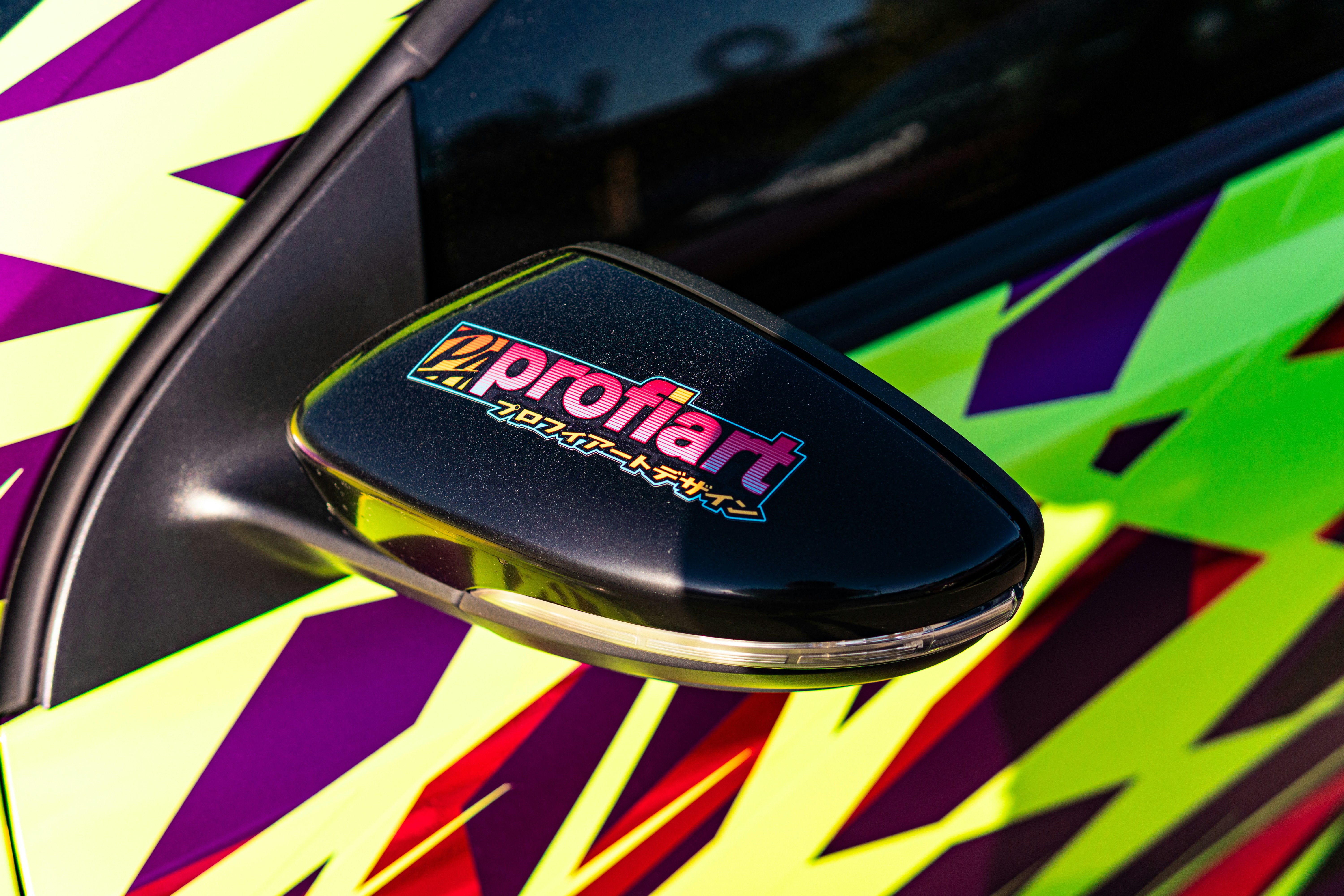Vibrant Prototart: Neon Patterns Framing a Car Mirror
