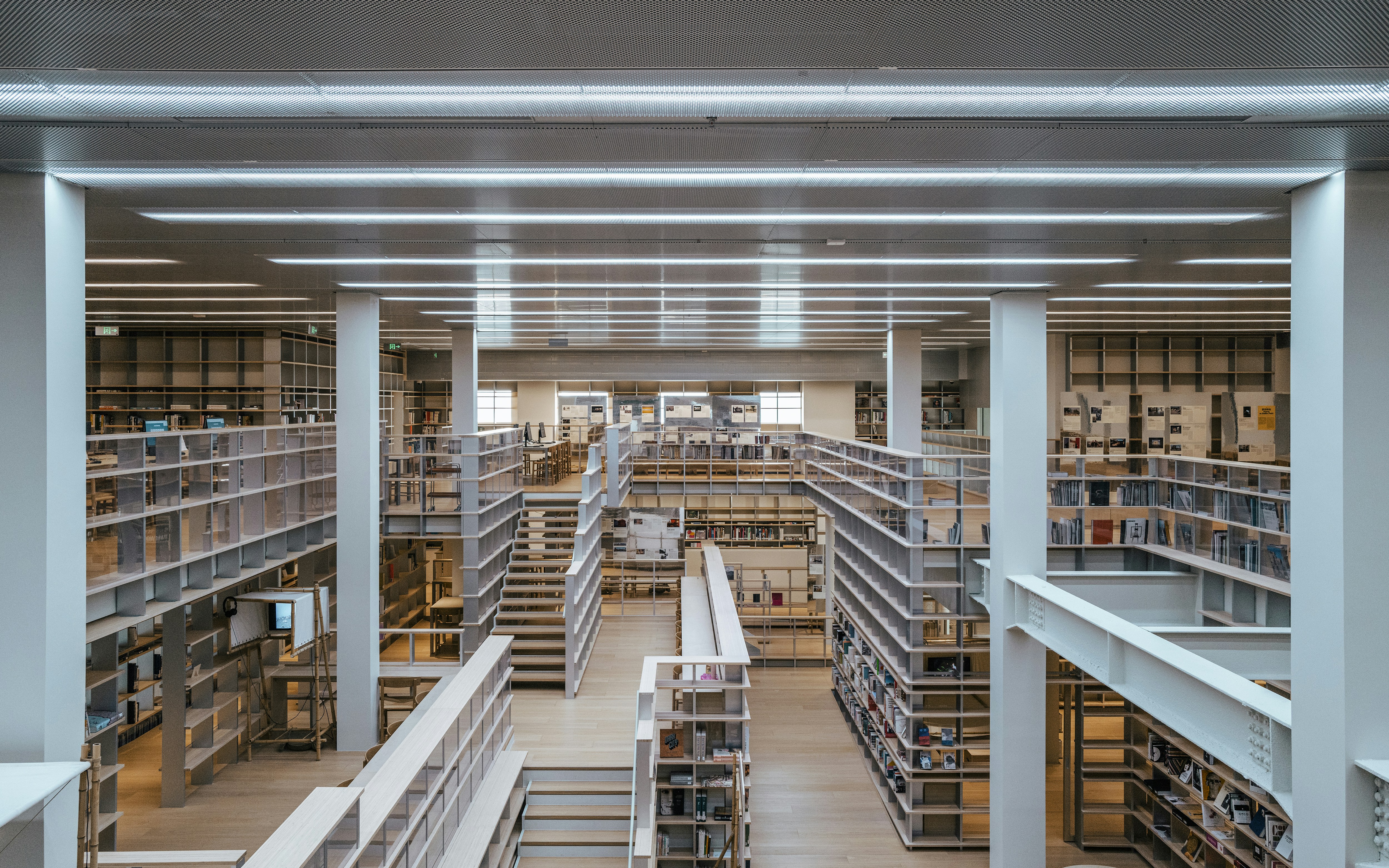 Modern library interior with many bookshelves and staircases.