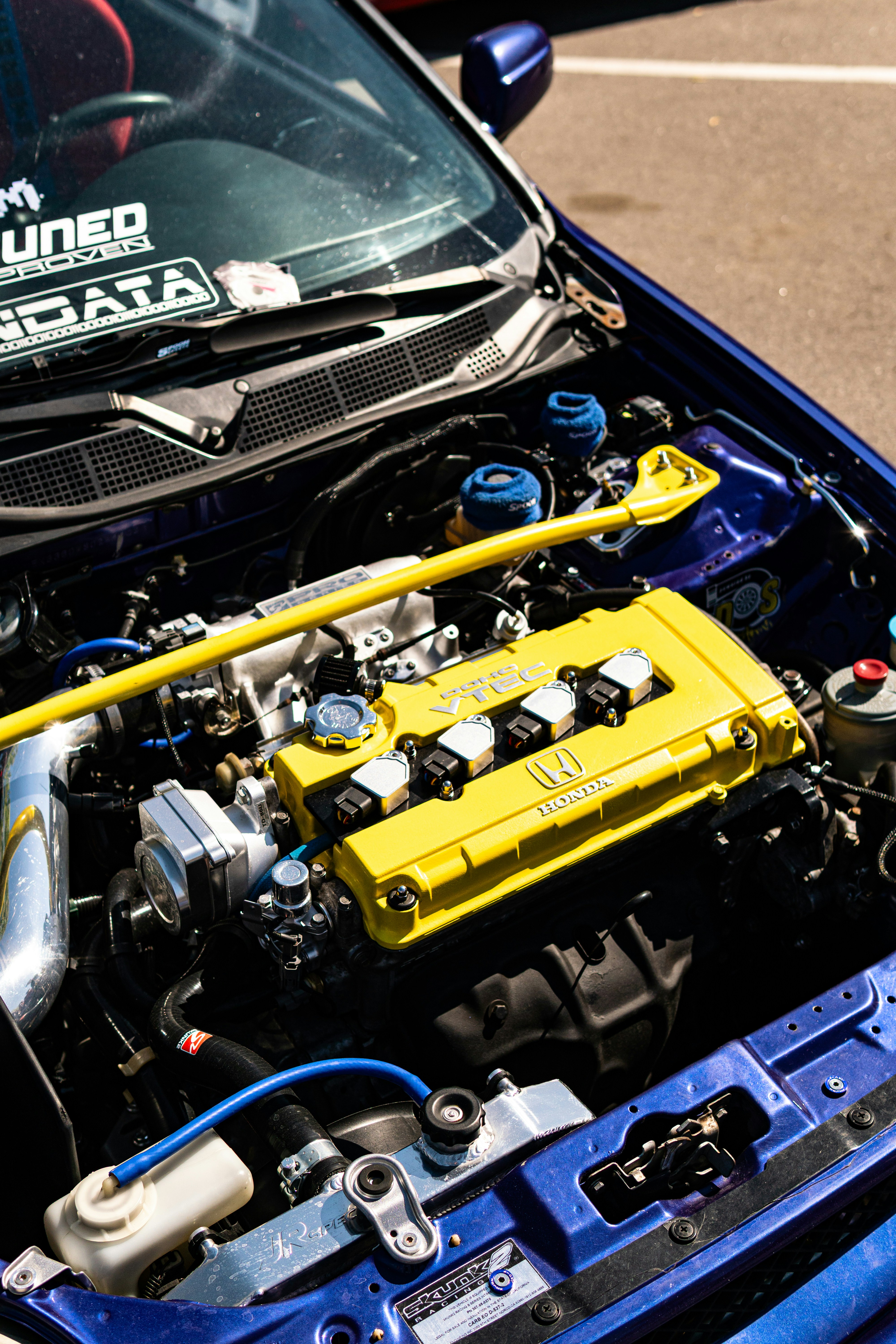 Yellow Cam cover under a polished blue hood: a close look at a tuned Honda engine