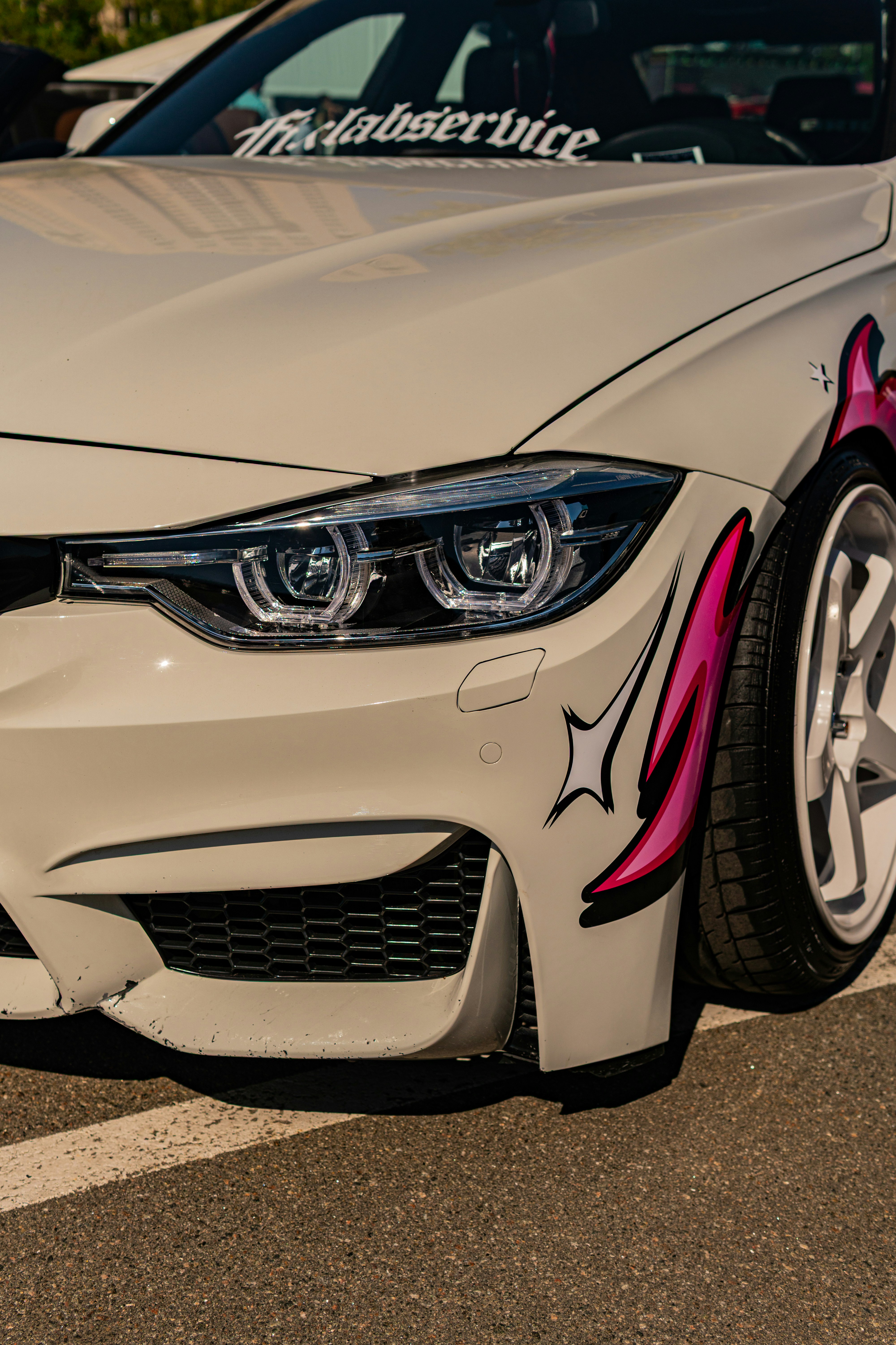Front Quarter of a Customized White Car with Pink Graphics