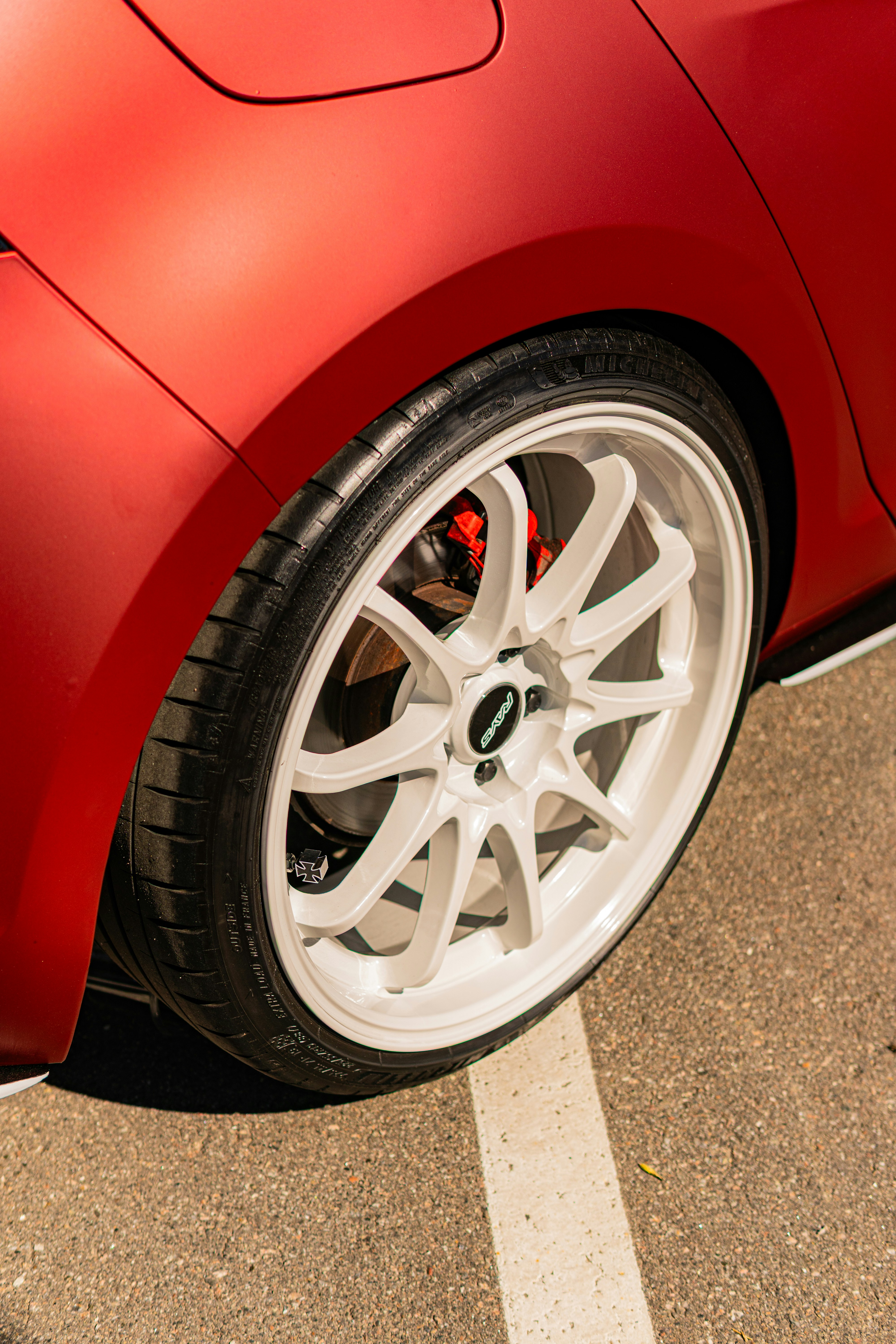 White-spoked wheel gleaming under a red curvaceous body