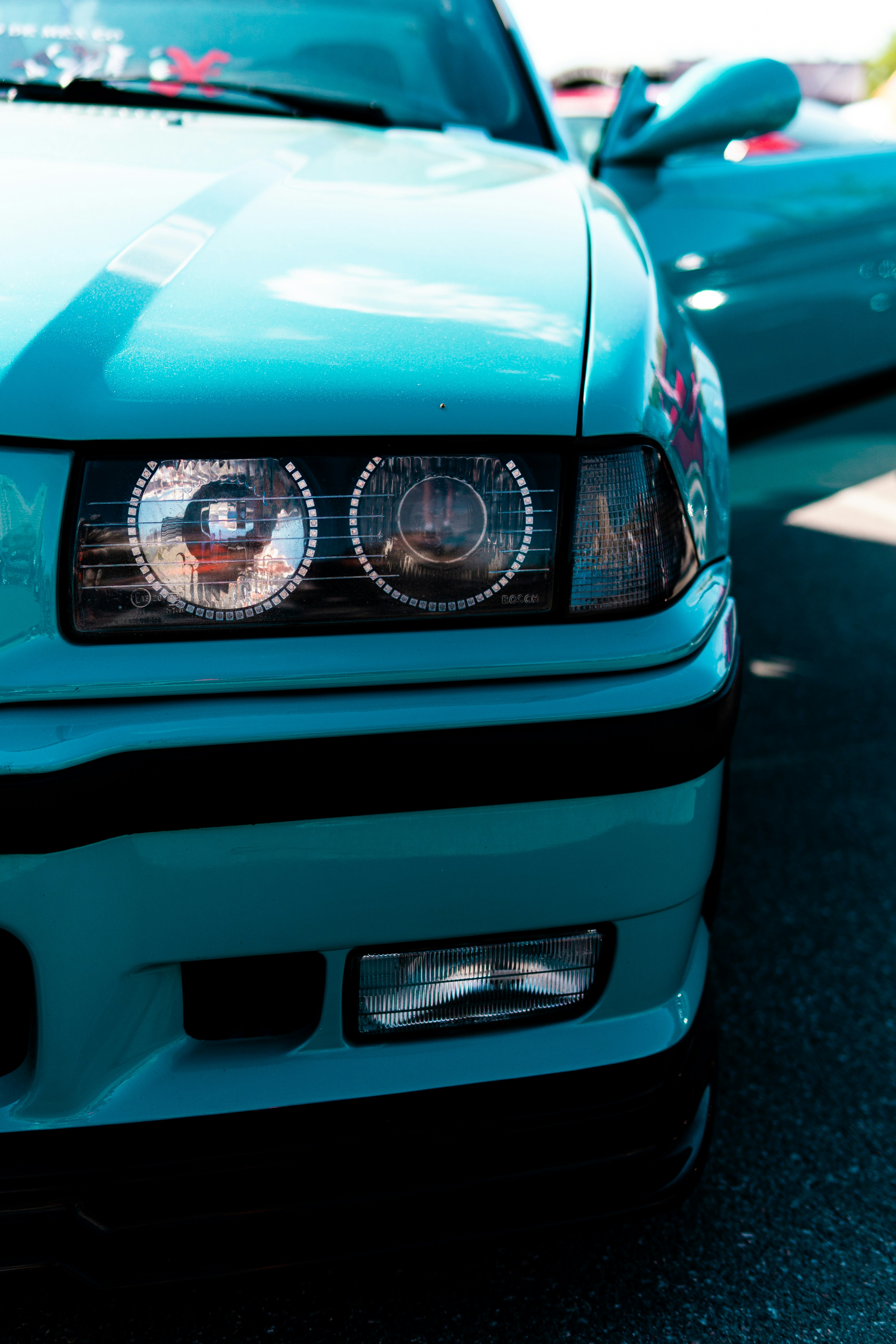 Close-Up of a Teal Sports Car: Headlights and Curved Hood in Focus