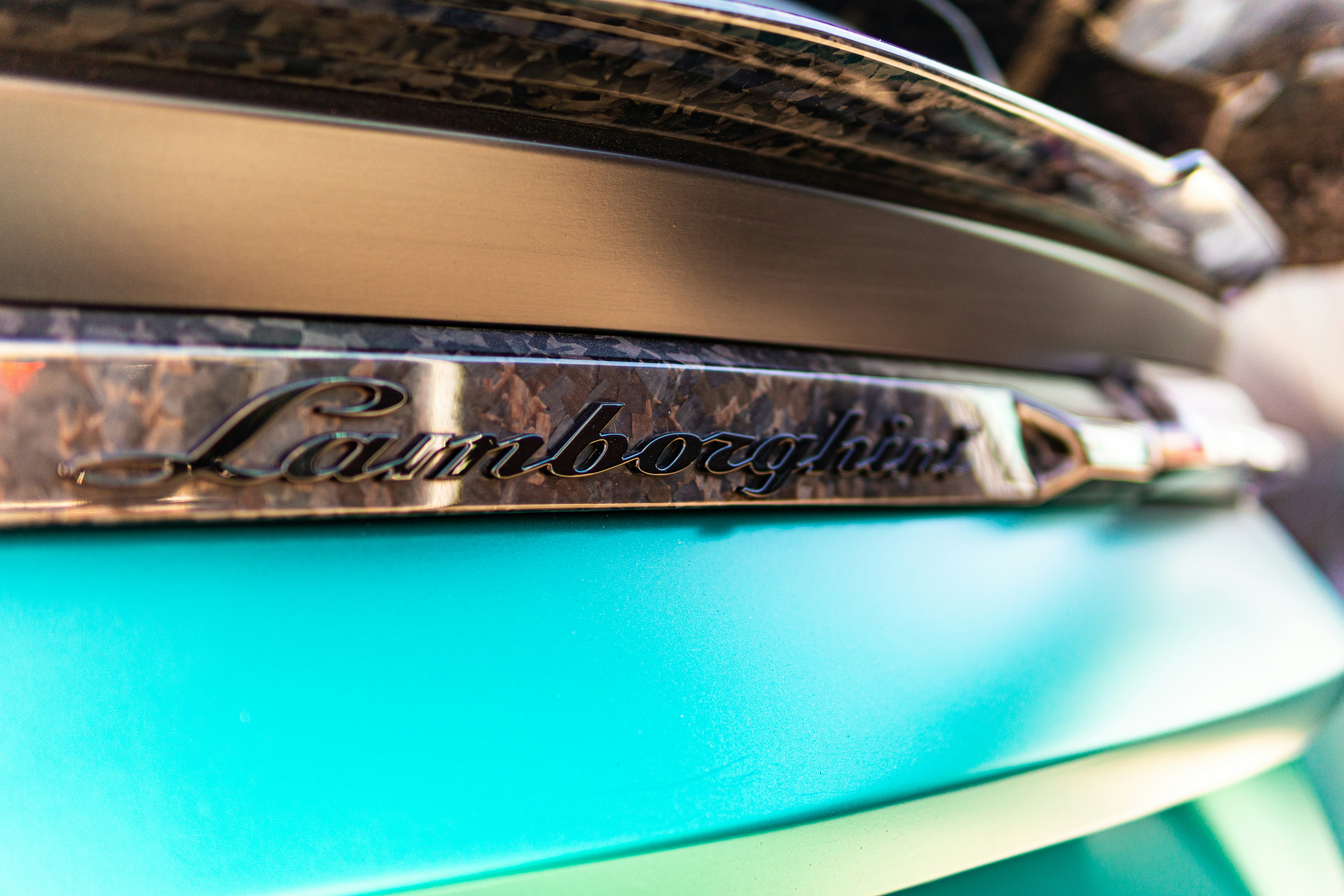 Chrome Script on a Teal Dream: The Lamborghini Badge Framed by Riverside Teal