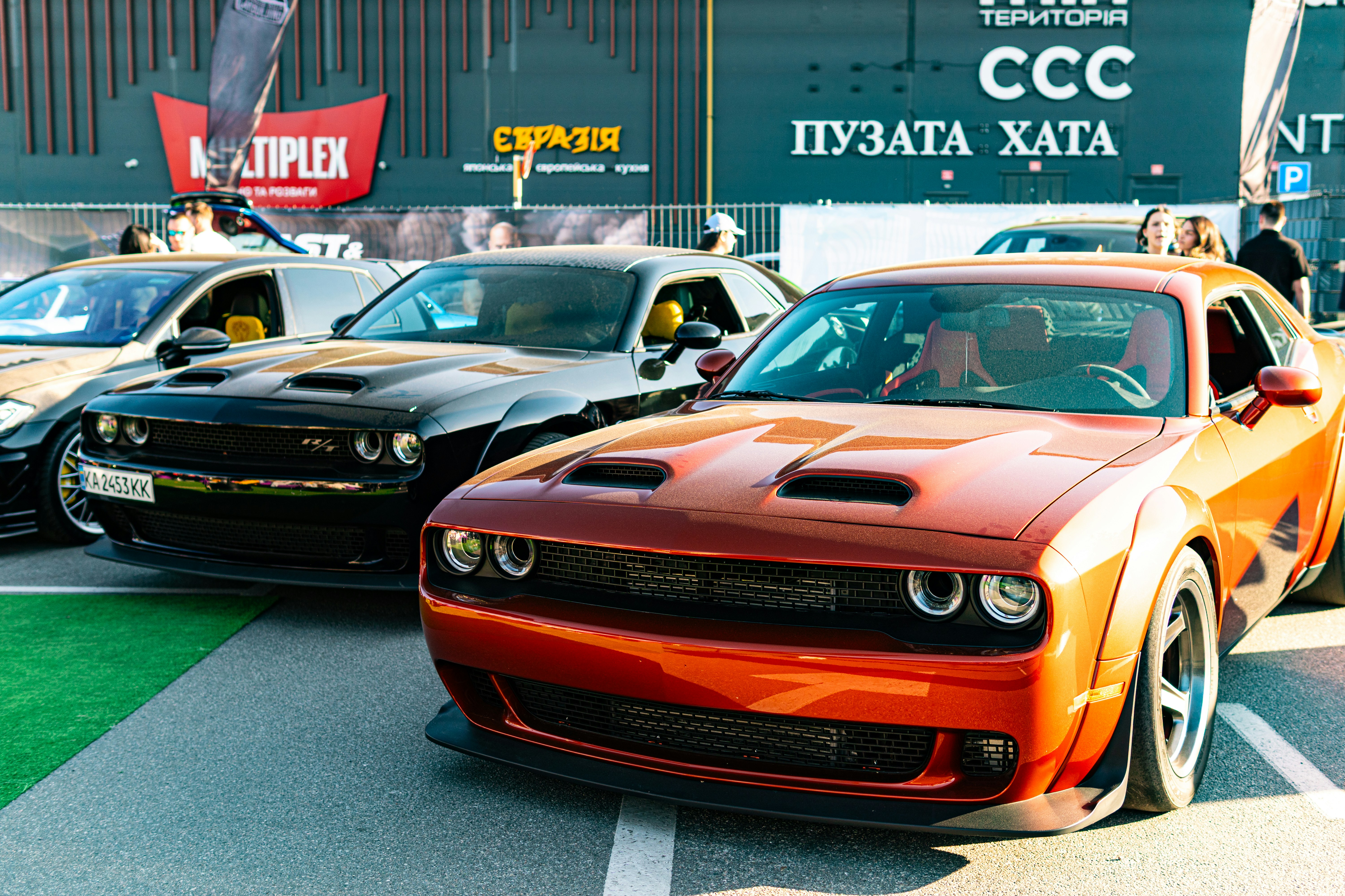 Orange Challenger Forward Lean: A Row of Race-Ready Muscle under Neon Signs