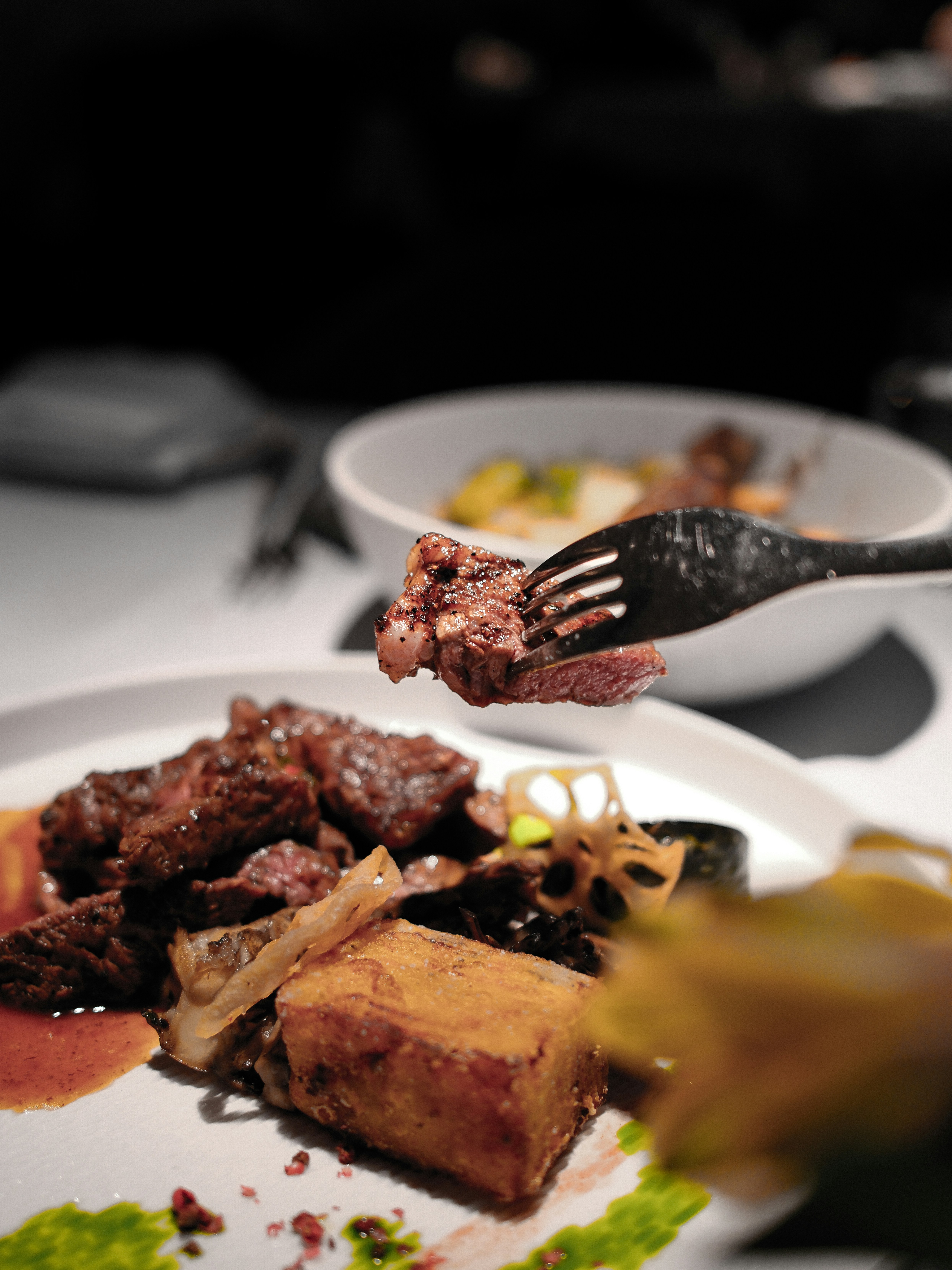 Tender Bite: Juicy Sliver of Steak Hovering Above a Golden, Crispy Square