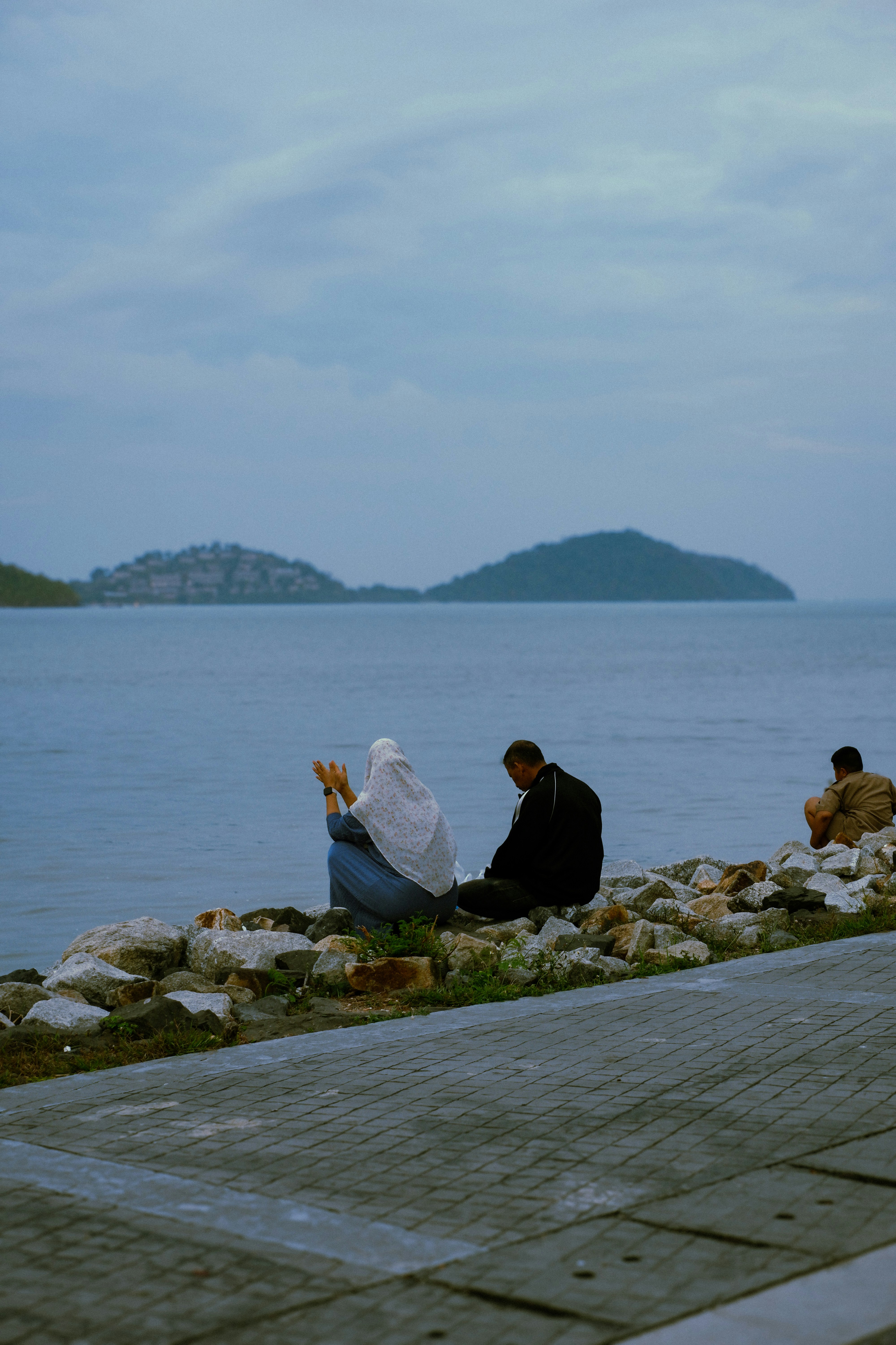 Quiet shoreline vigil: three figures by the water’s edge