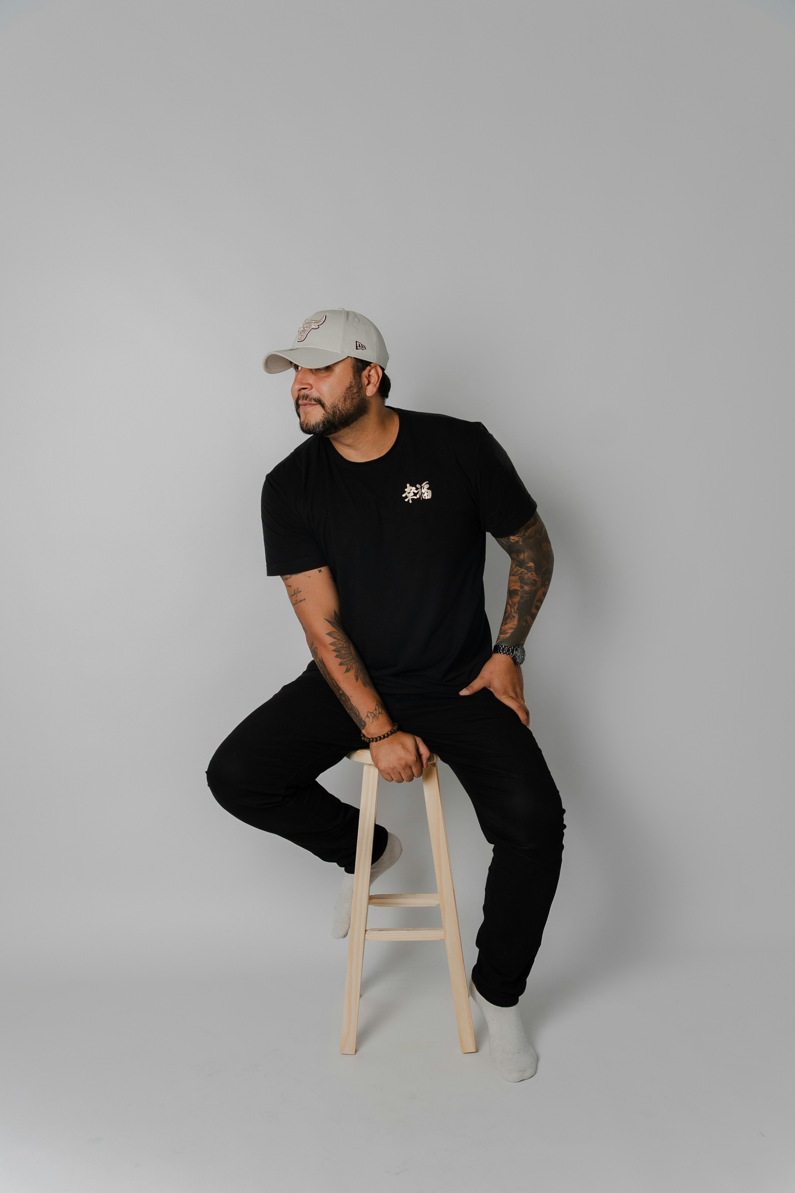 Casual Confidence: Man on a Stool Against a Minimal Studio Backdrop