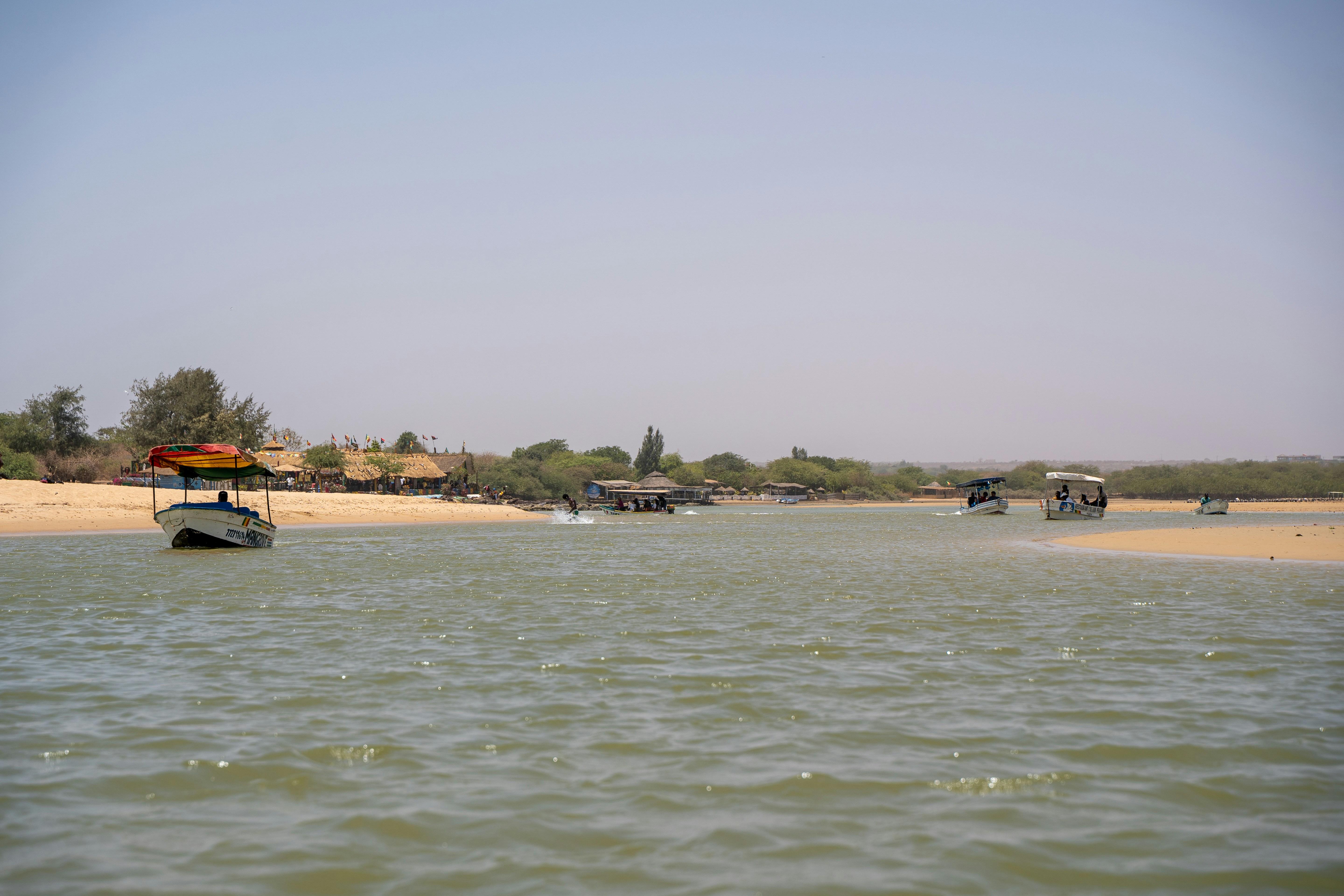 Foamy shoreline and boats at a sunlit river delta