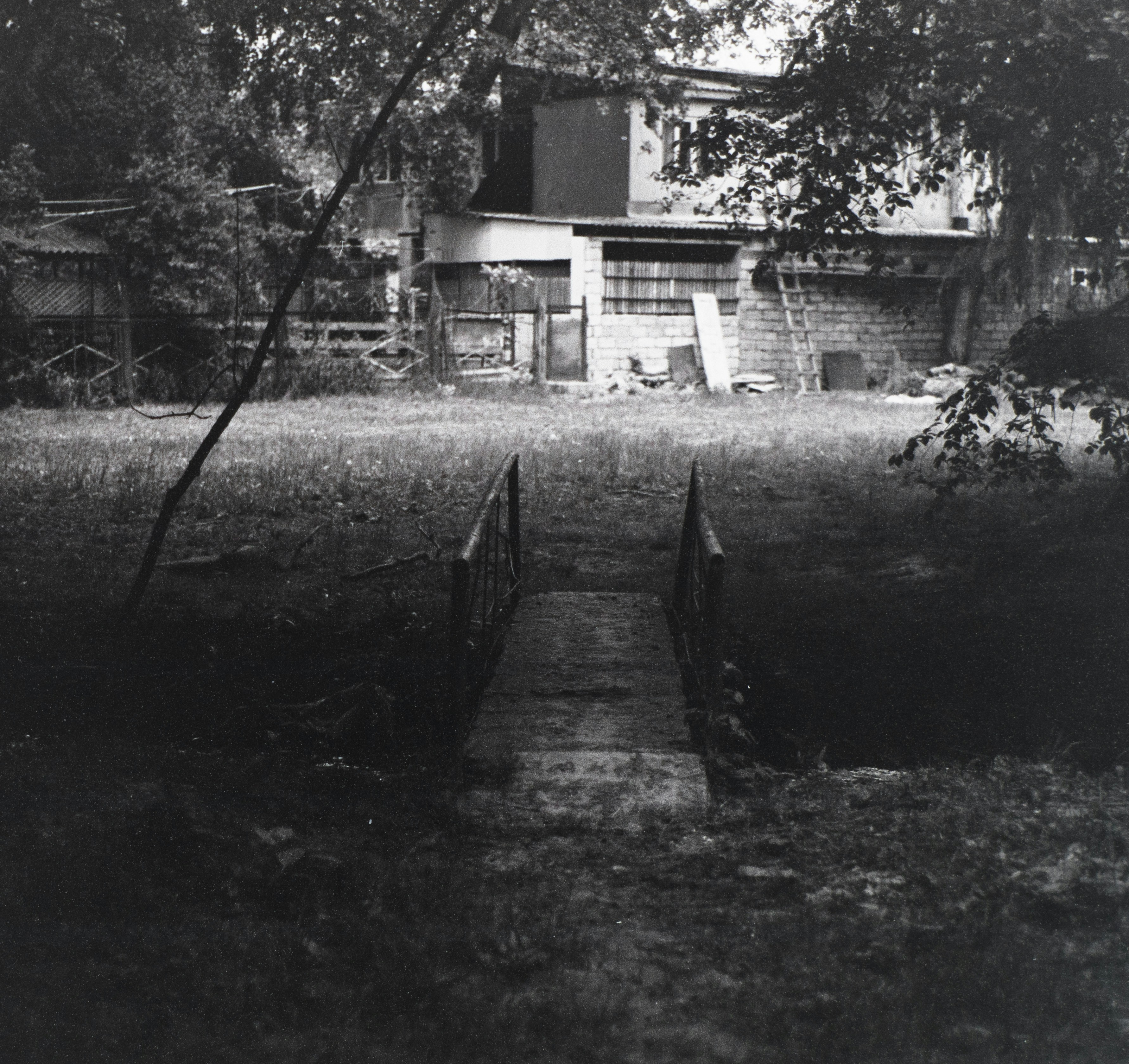 Abandoned walkway to a weathered building remembered by trees