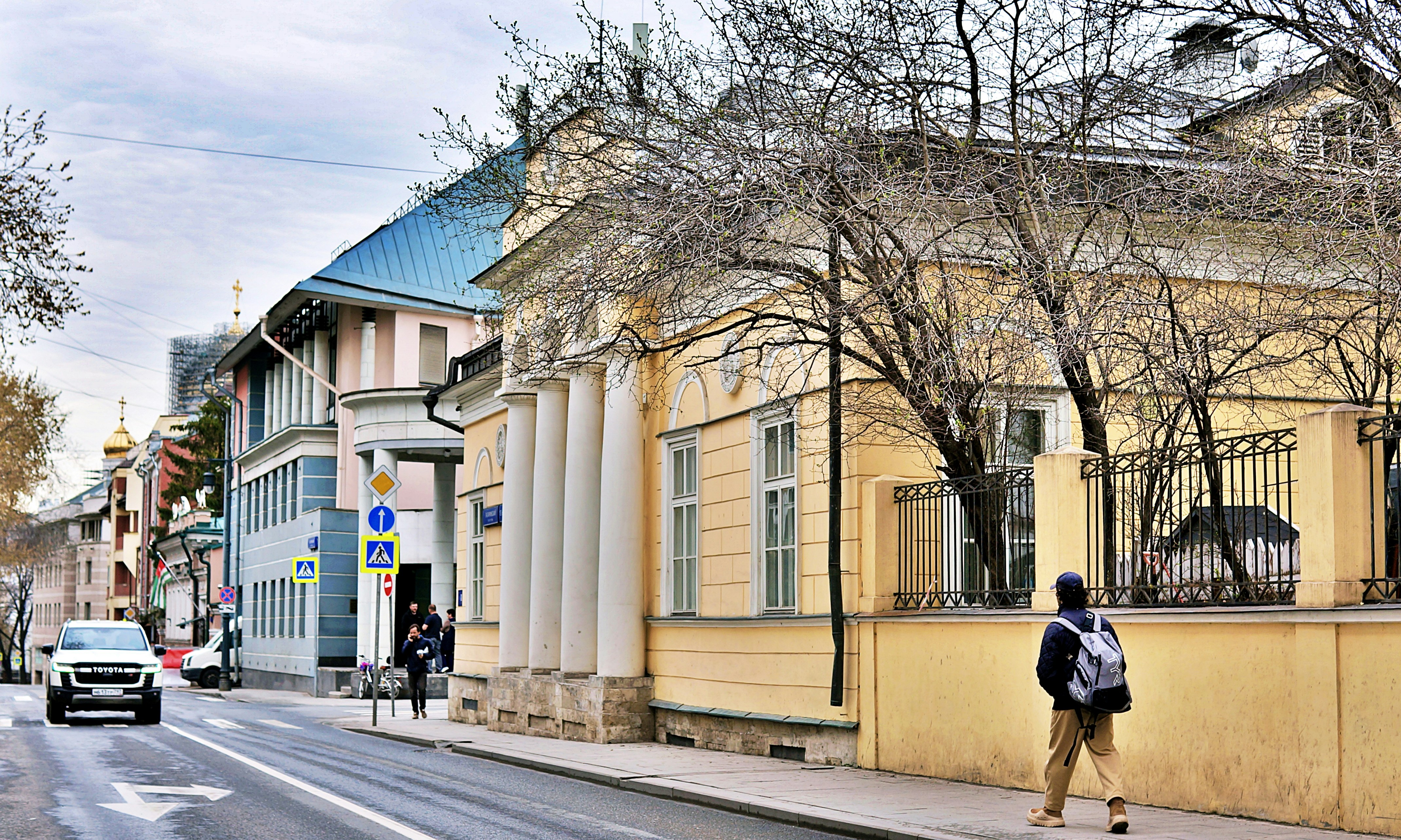 Lone Pedestrian in a Sunlit European Street
