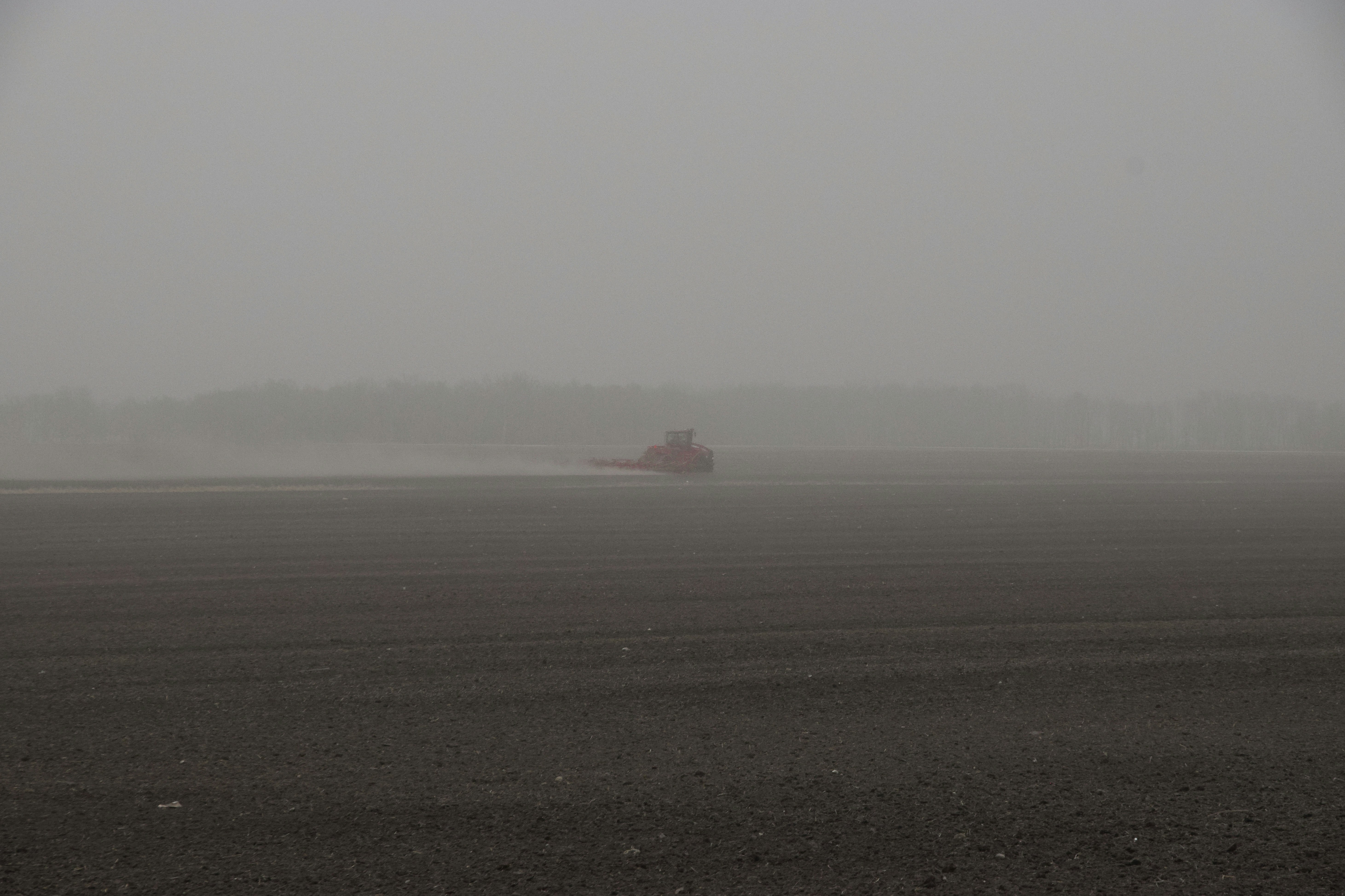 Mist on the Tilled Field: A Distant Red Tractor in Quiet Fog