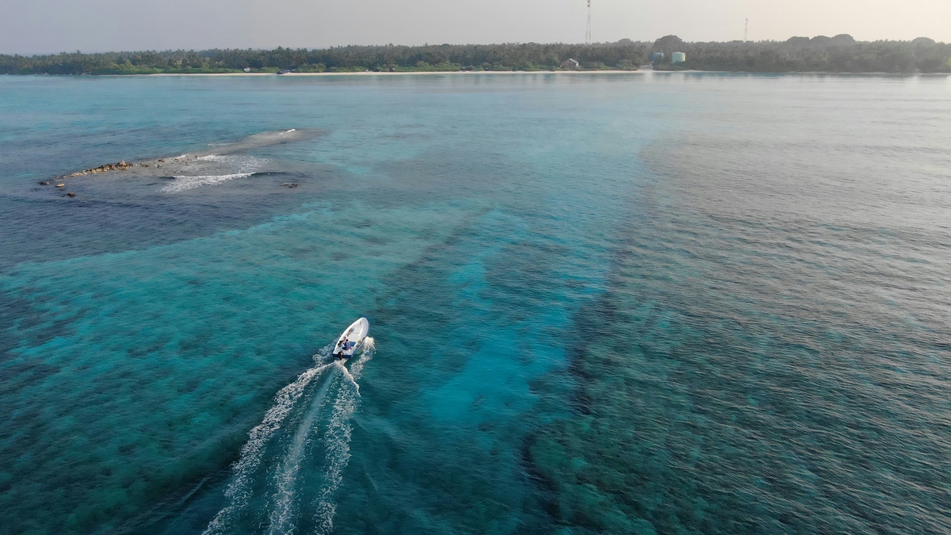 Electric Turquoise Wake: A Boat Slips Across Reef-blue Waters