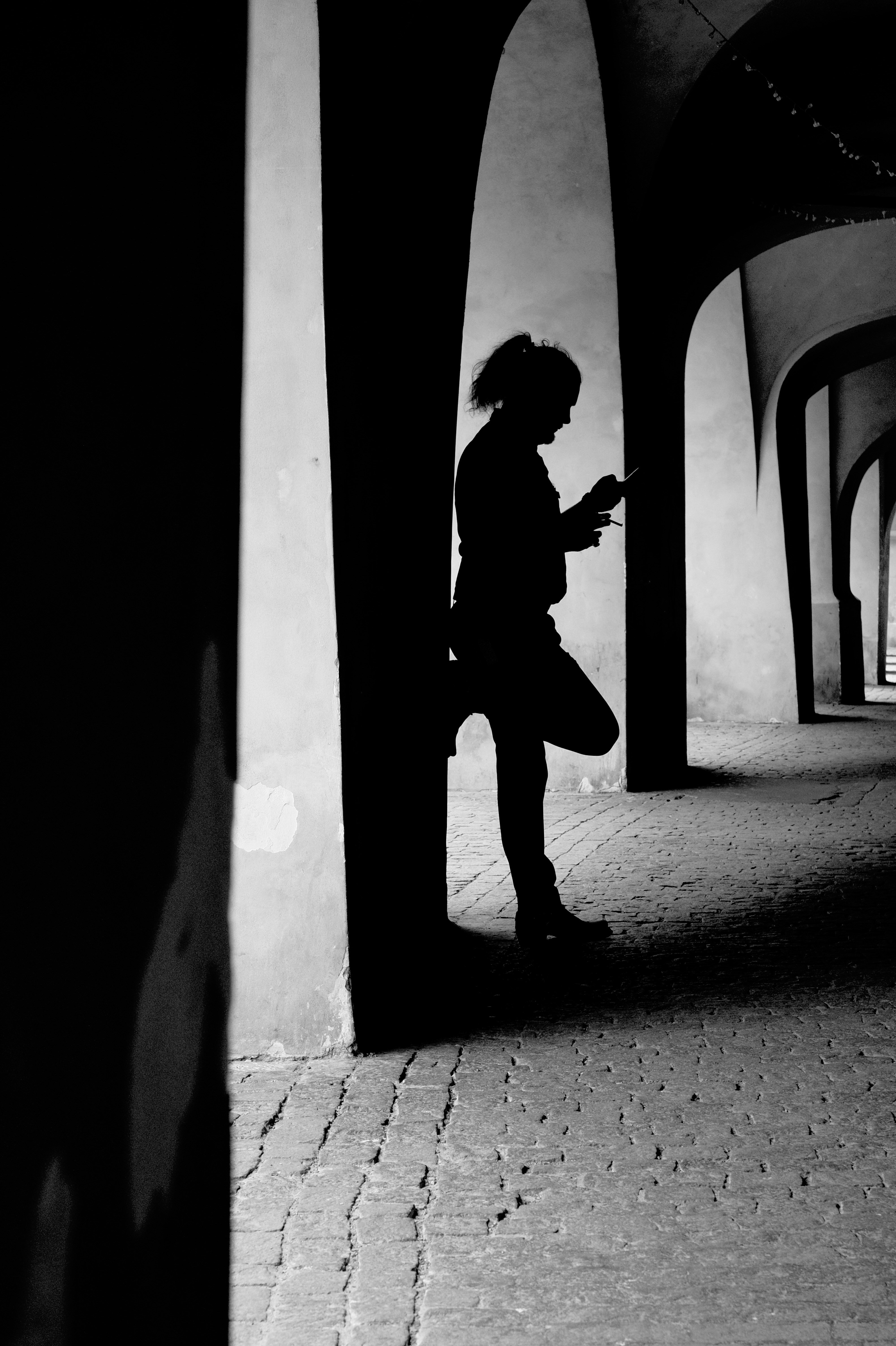 Silhouette in the Archway: A Quiet Moment with a Tablet
