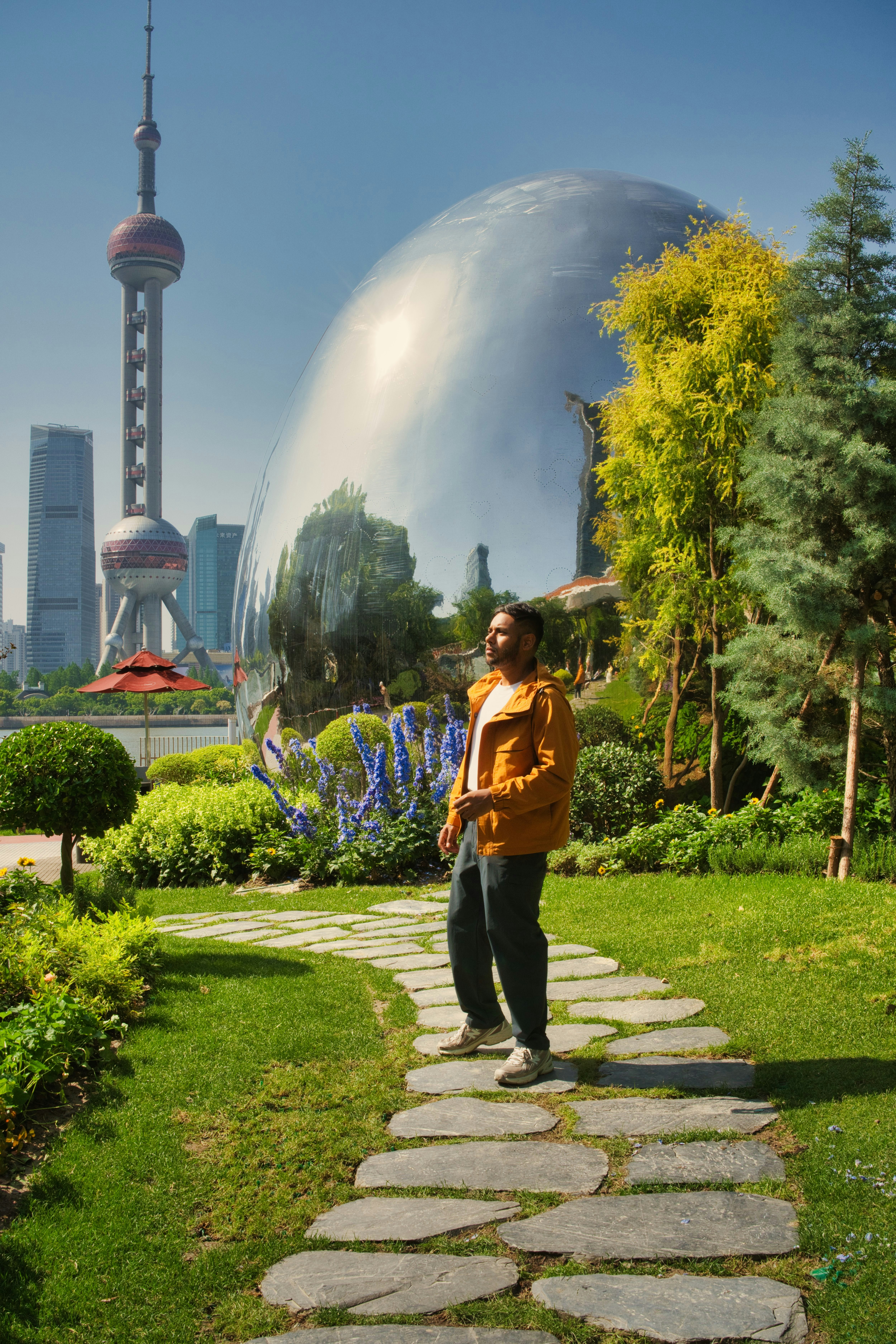 Man in park with city skyline and large reflective sculpture.