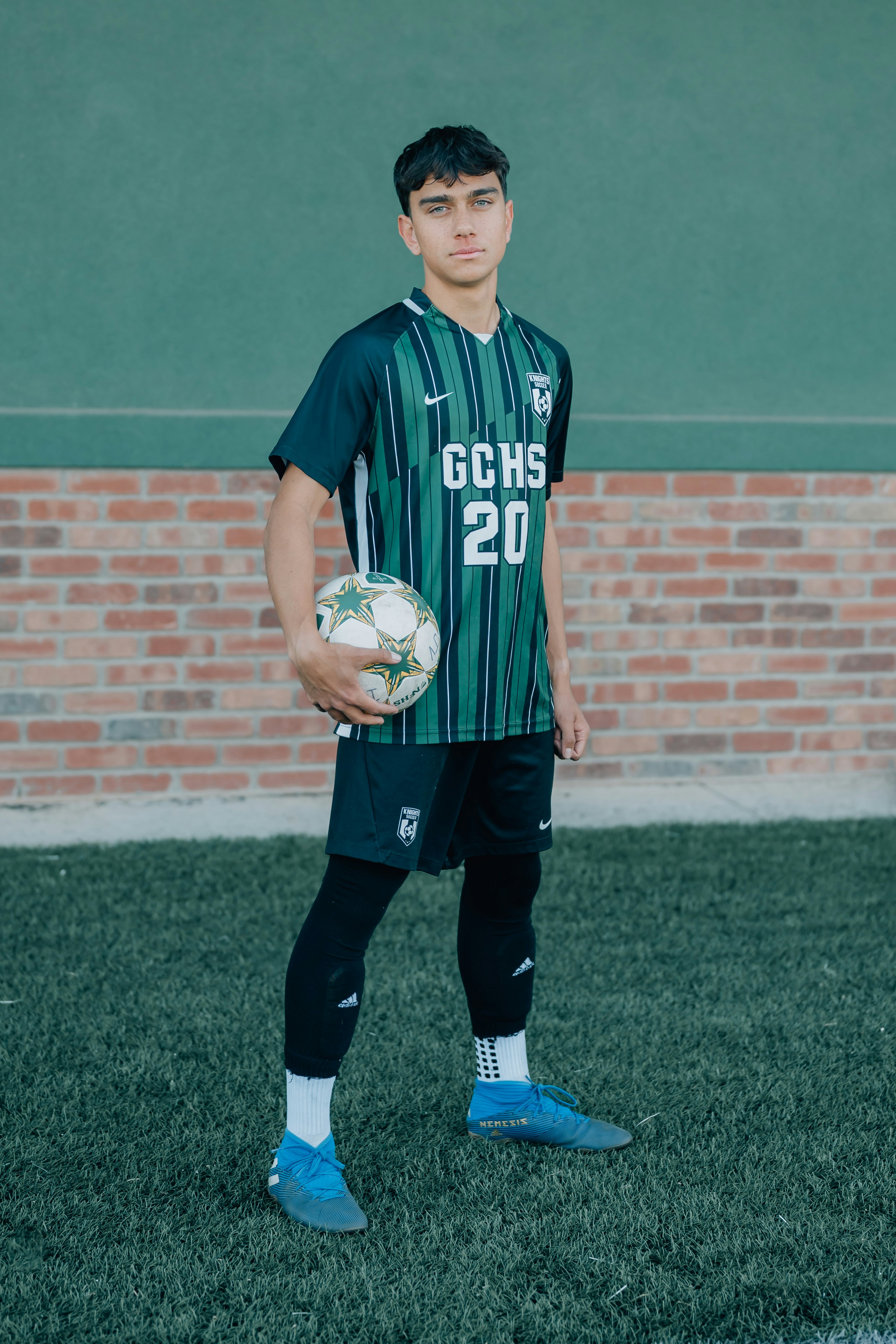 Portrait of a young soccer player with a ball against a brick backdrop