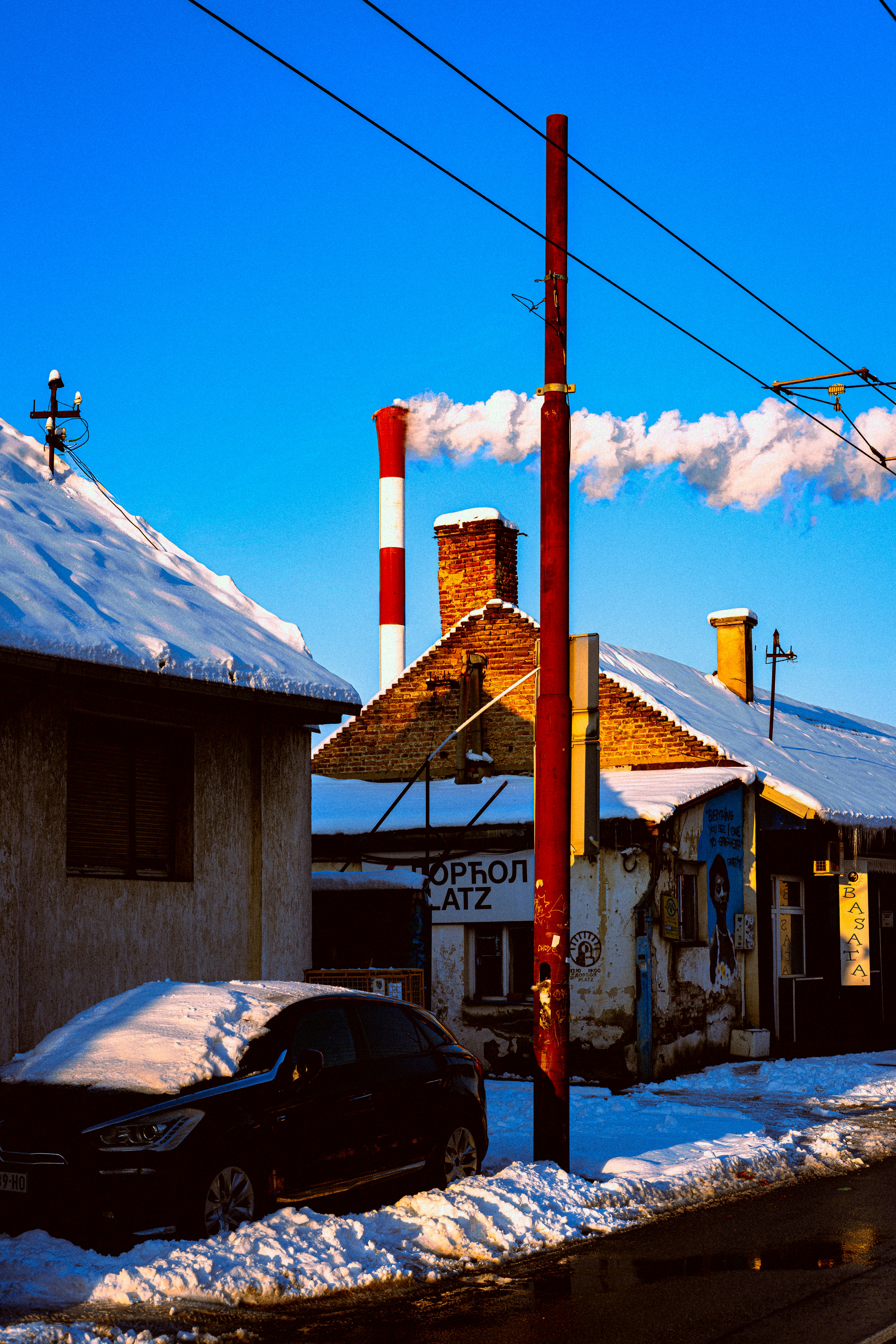 Snow-Covered Street with Power Lines and Bright Chimneys