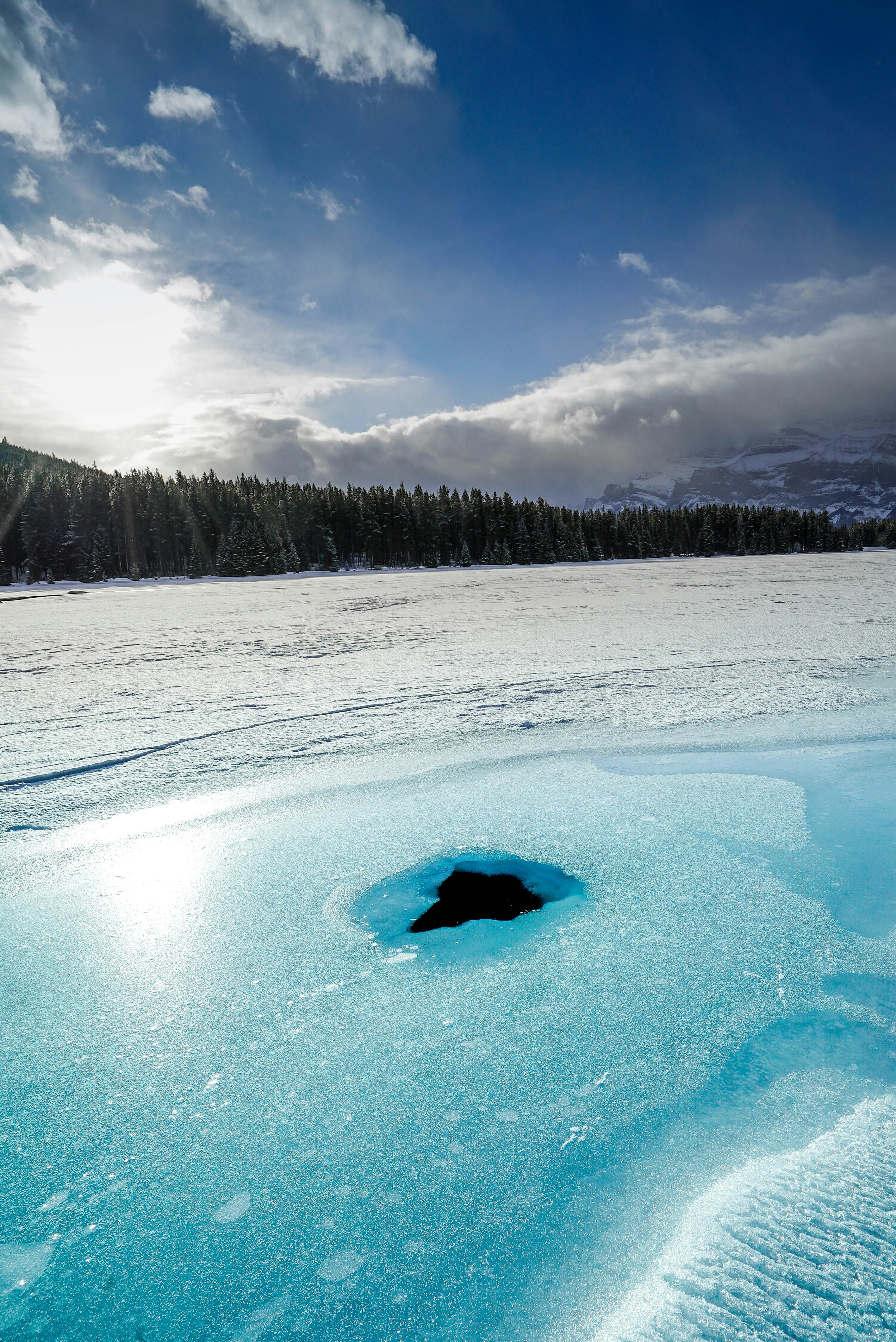 Sunlit Fjord: A Snow-Carpeted Lake with a Glacial Hole