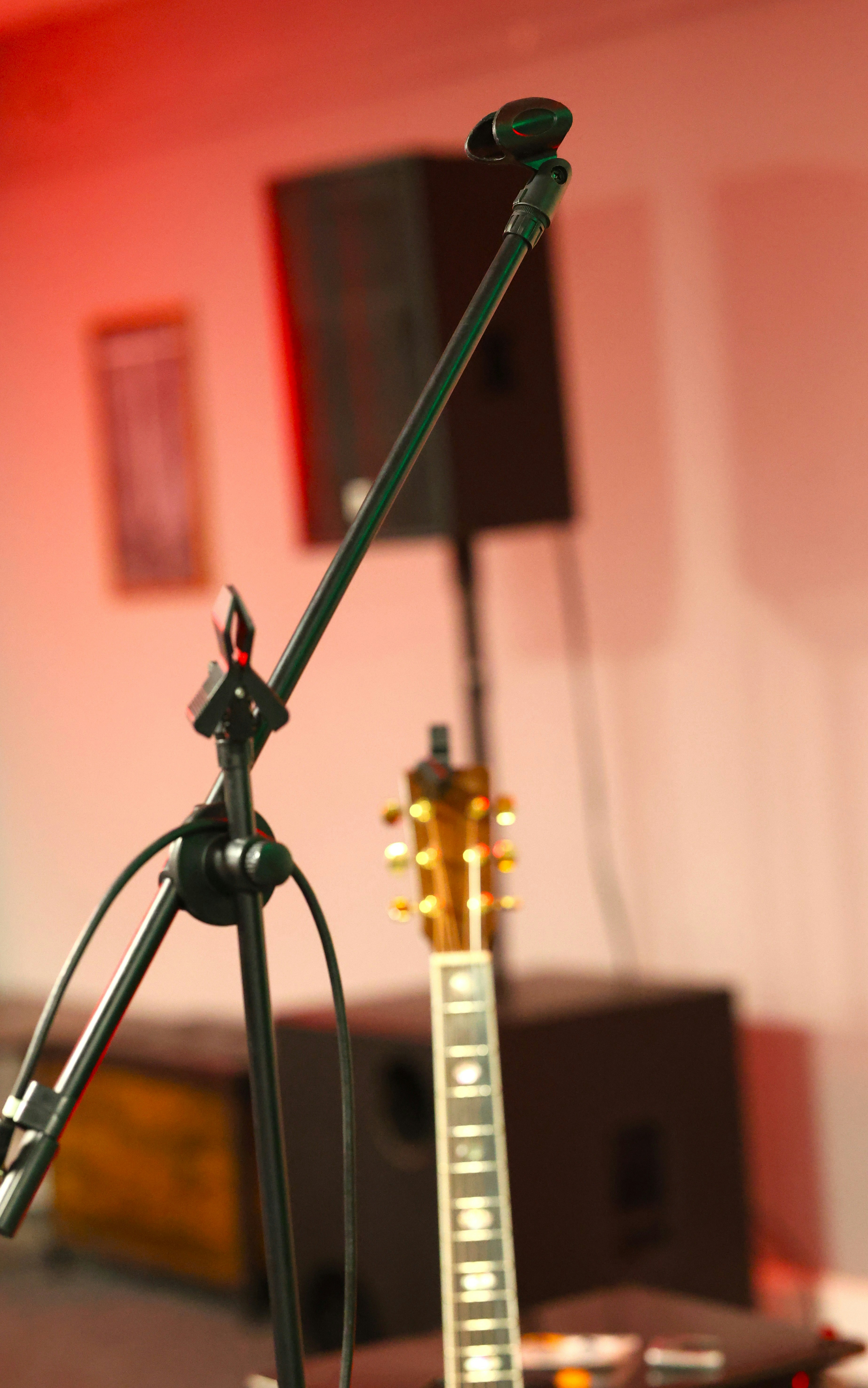 Silent Stage: Microphone Stand and Guitar in a Dim Studio
