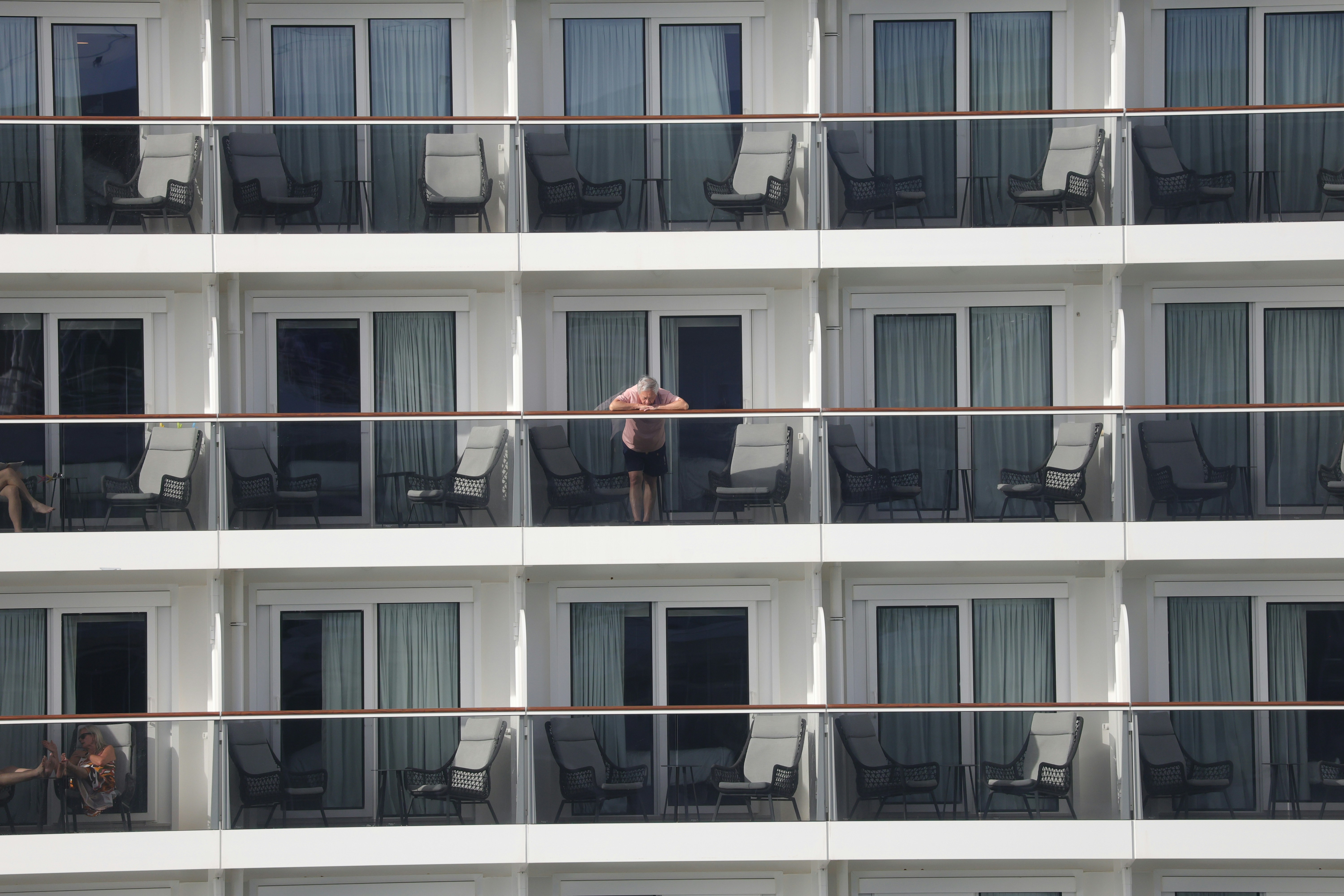 Centered on the Balcony Silhouette: A lone figure amid repetitive balconies