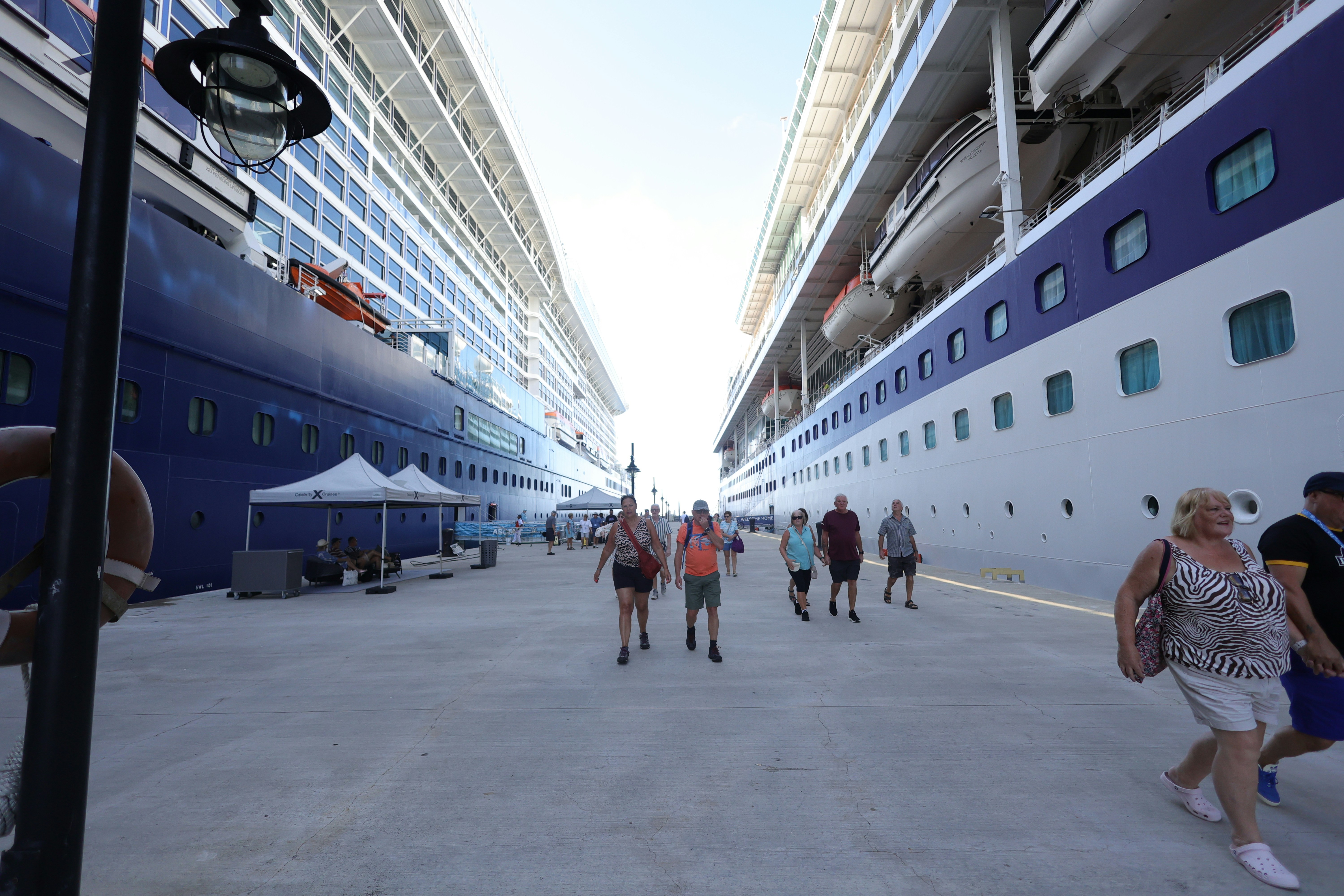 Dockside Parade: People Stroll Between Monarchs at Pier Deck