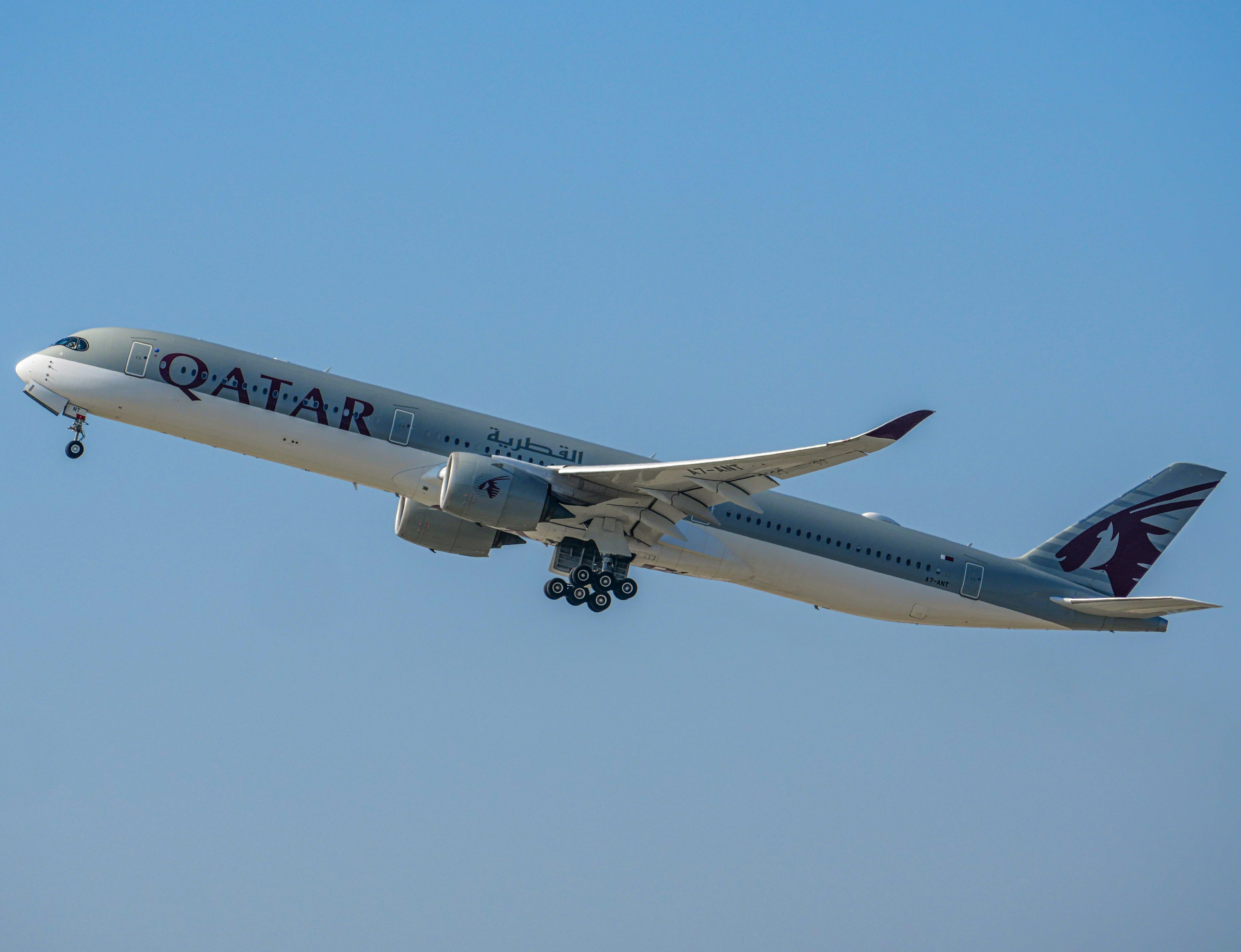 Qatar Airways A350-style silhouette lifting against a clear blue sky