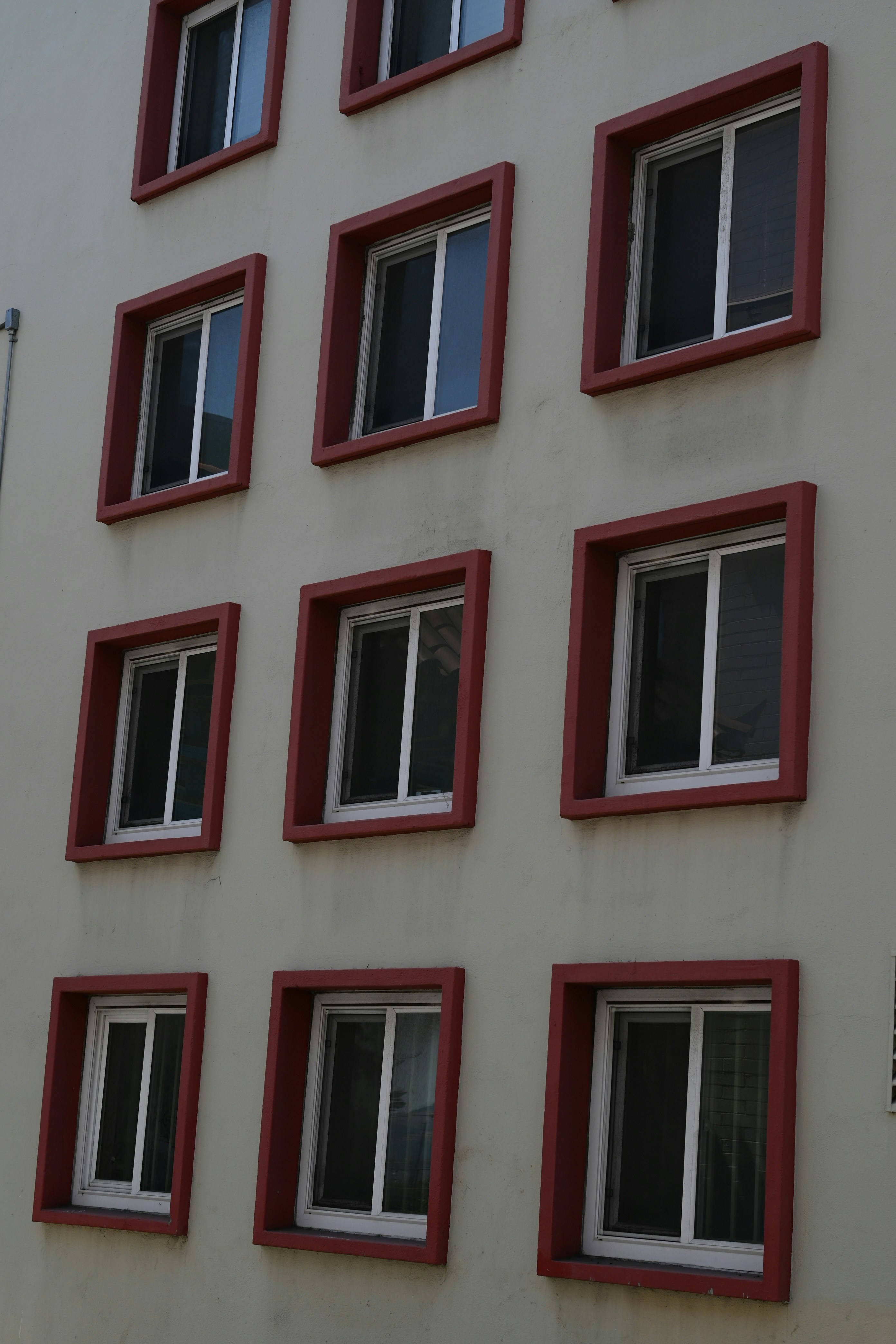 Grid of Red-Framed Windows on a Pale Facade