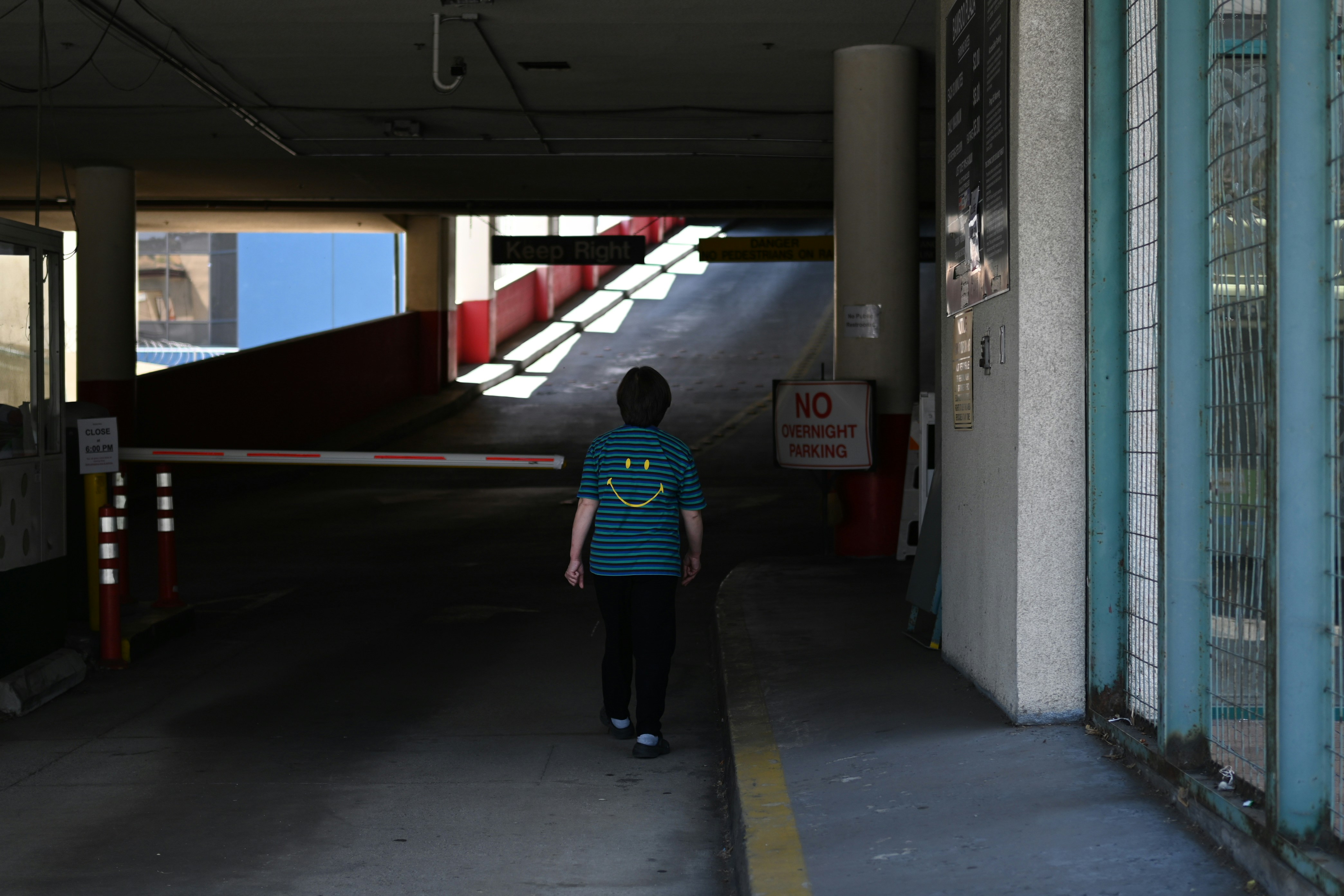 A person walks through a dimly lit parking garage.