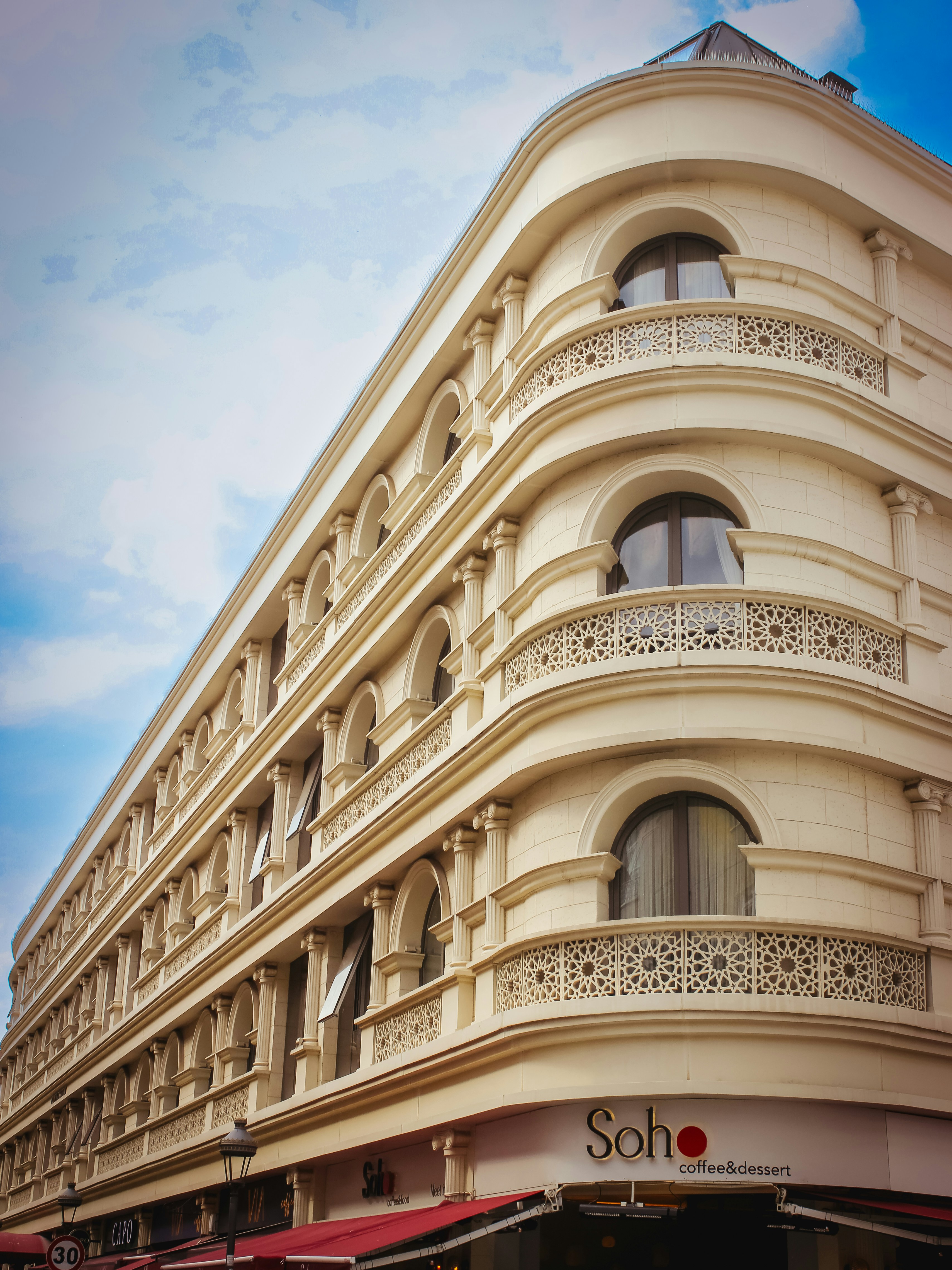 Curved Facade Panorama: A Corner-Grounded Hotel Between Sky and Street