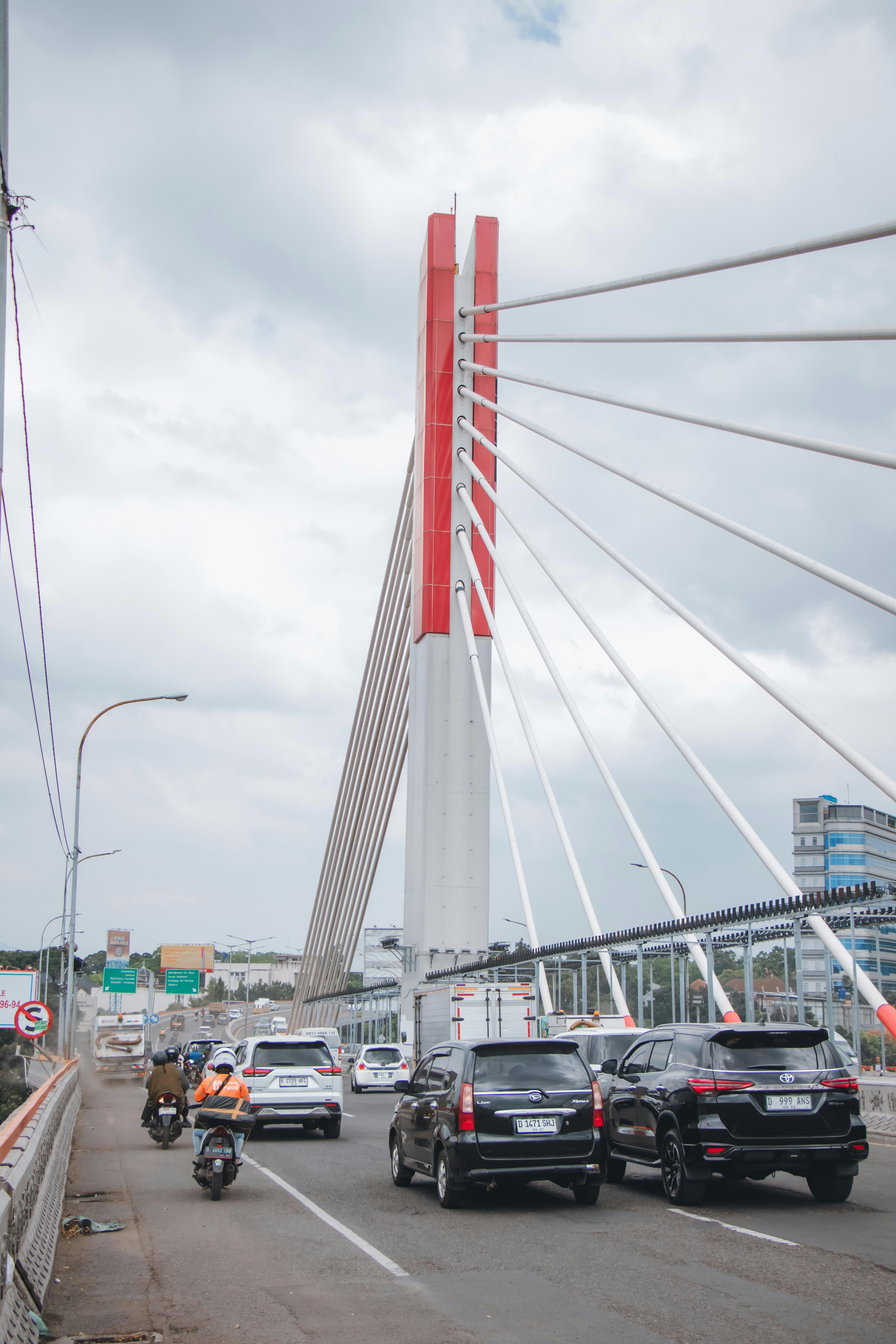 Red Cable-Driven Tower Over a Busy Bridge