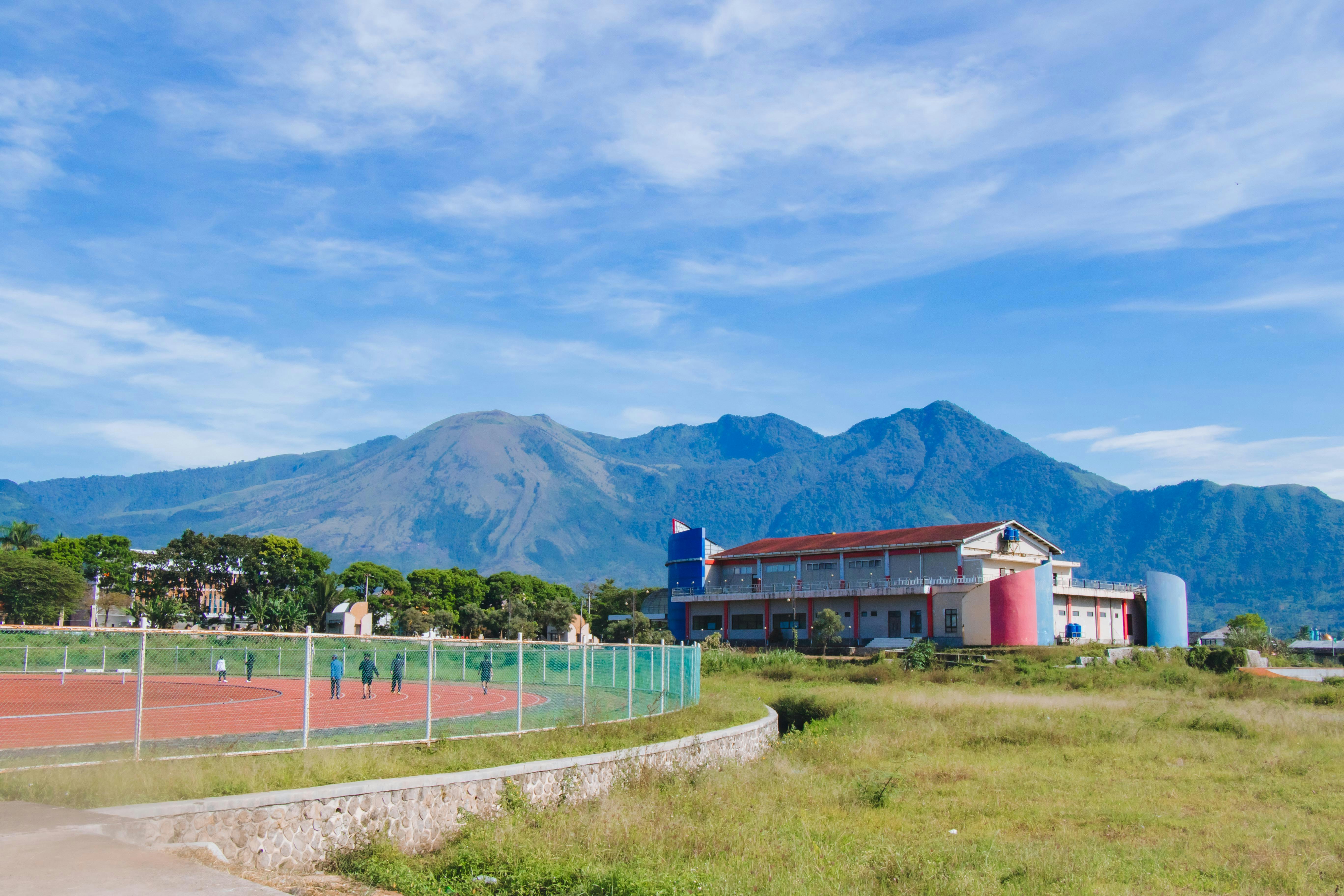 Sunny Sports Field with Mountain Backdrop and Modern Facility