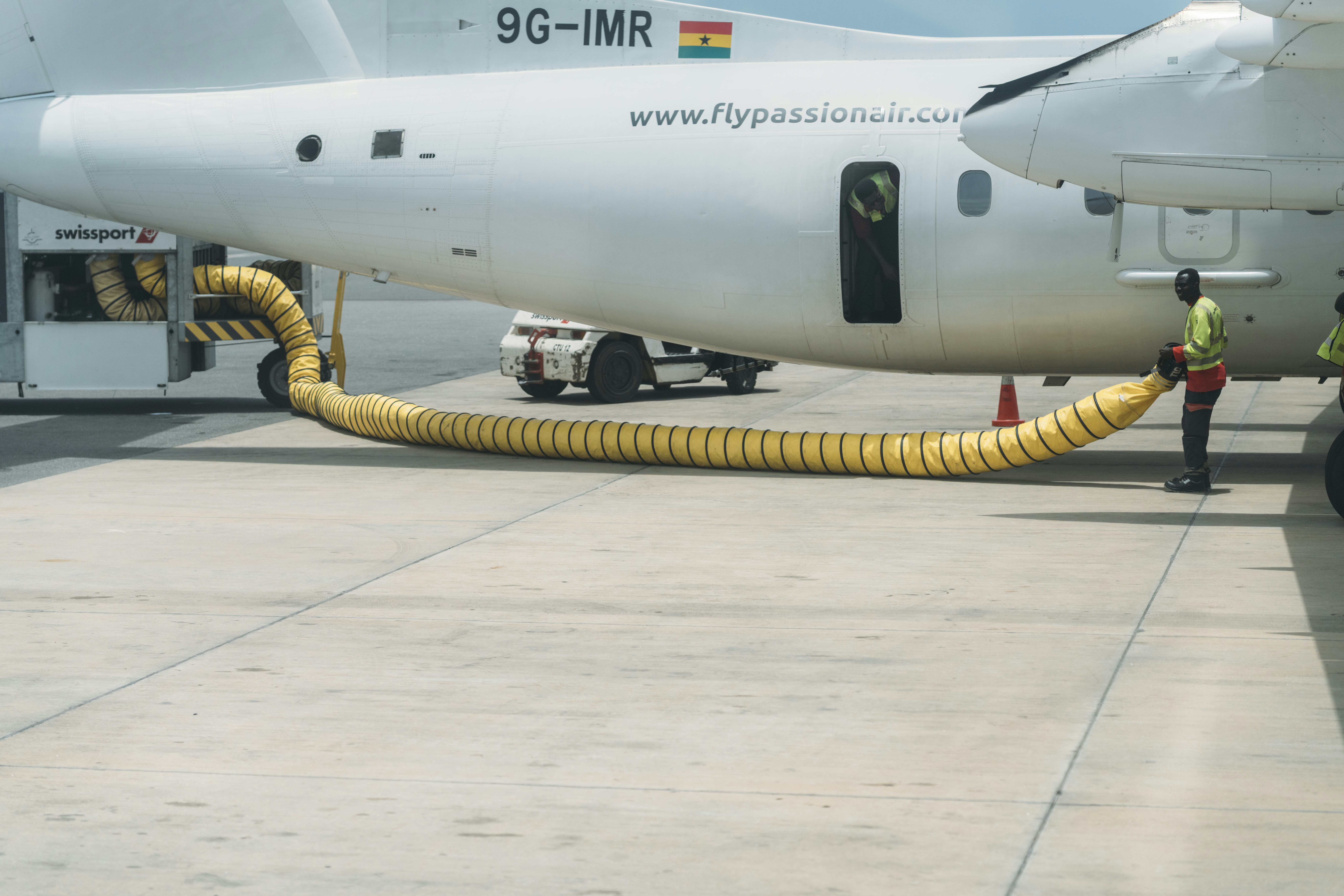 Ground Crew at the Tailwind: A Passenger Jet Connected to a Yellow Duct for Ground Power