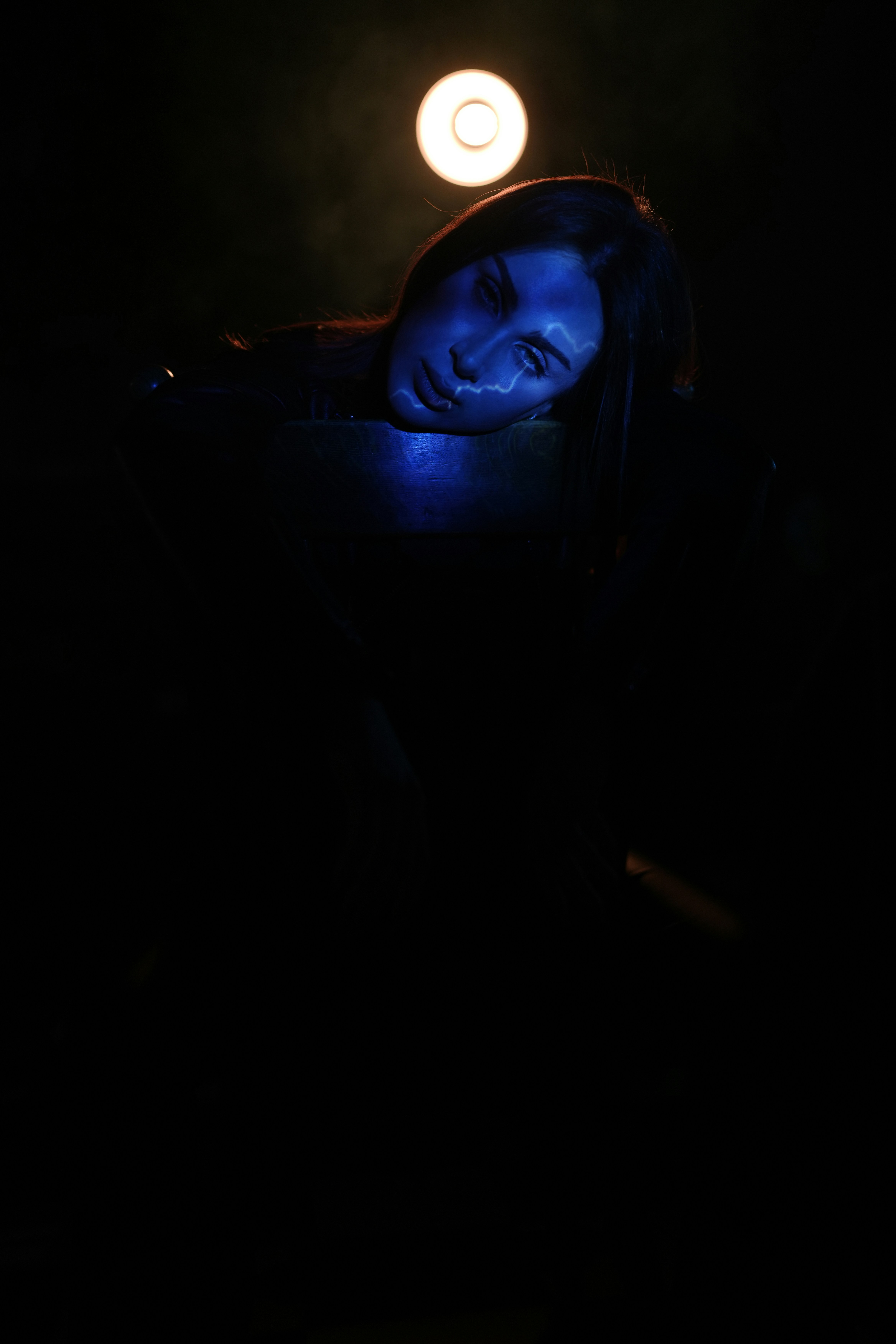 Blue-lit Contemplation: Head resting on a chair under backlight
