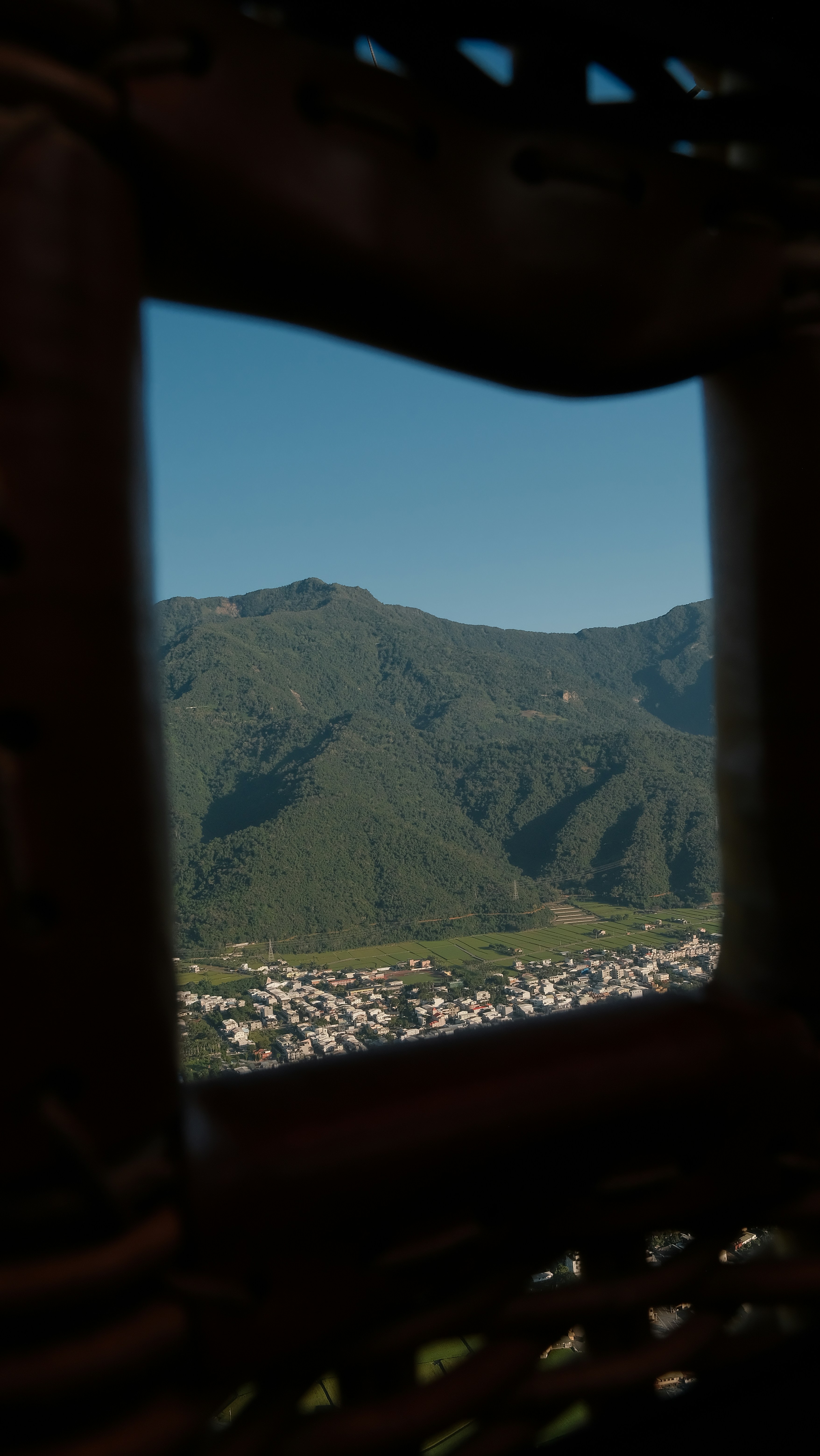 Through the Ironwork: A Mountain Village Framed by Braced Arch