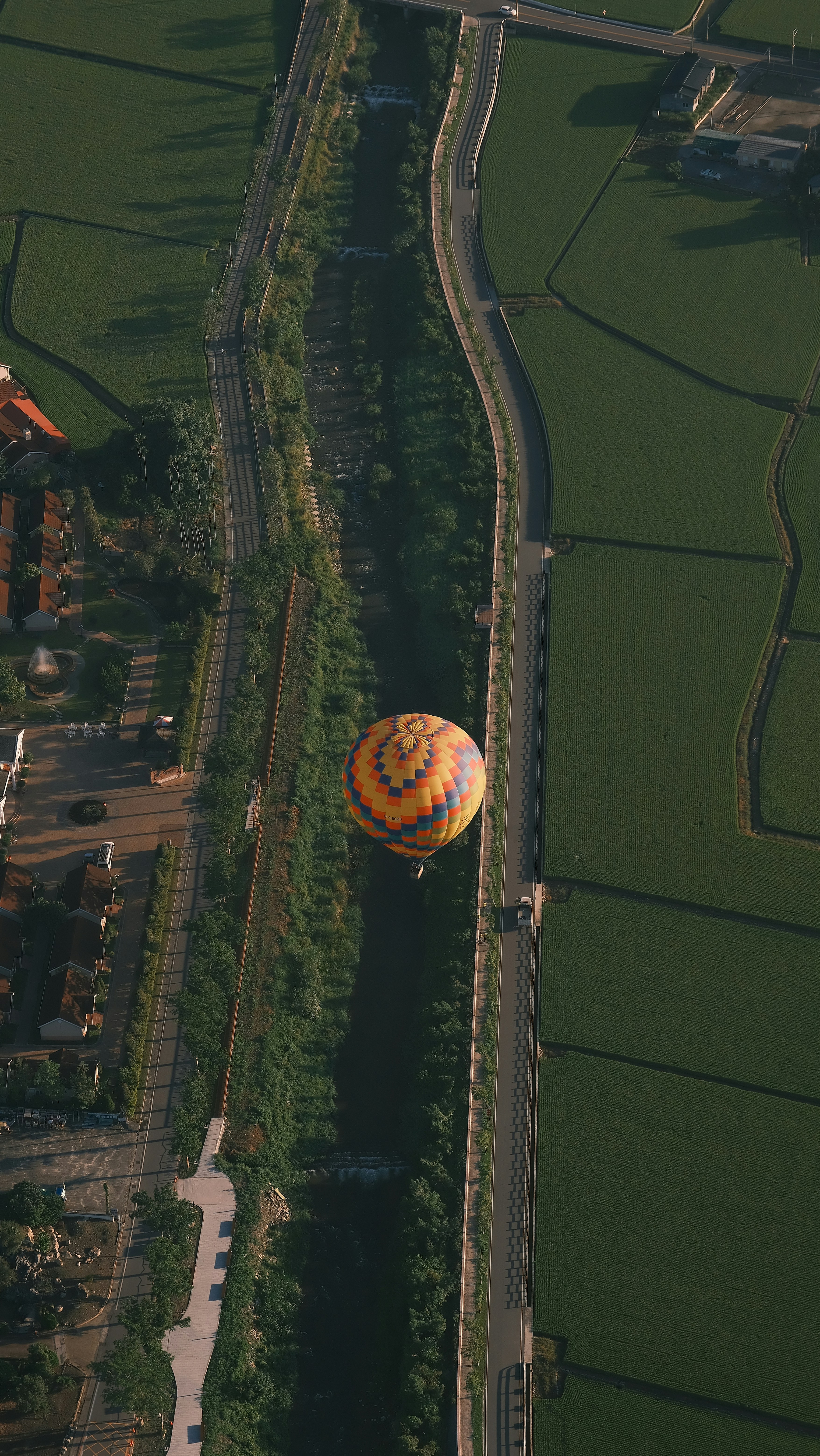 Floating Ember: A Vibrant Balloon Drifts Over a Riverine Corridor