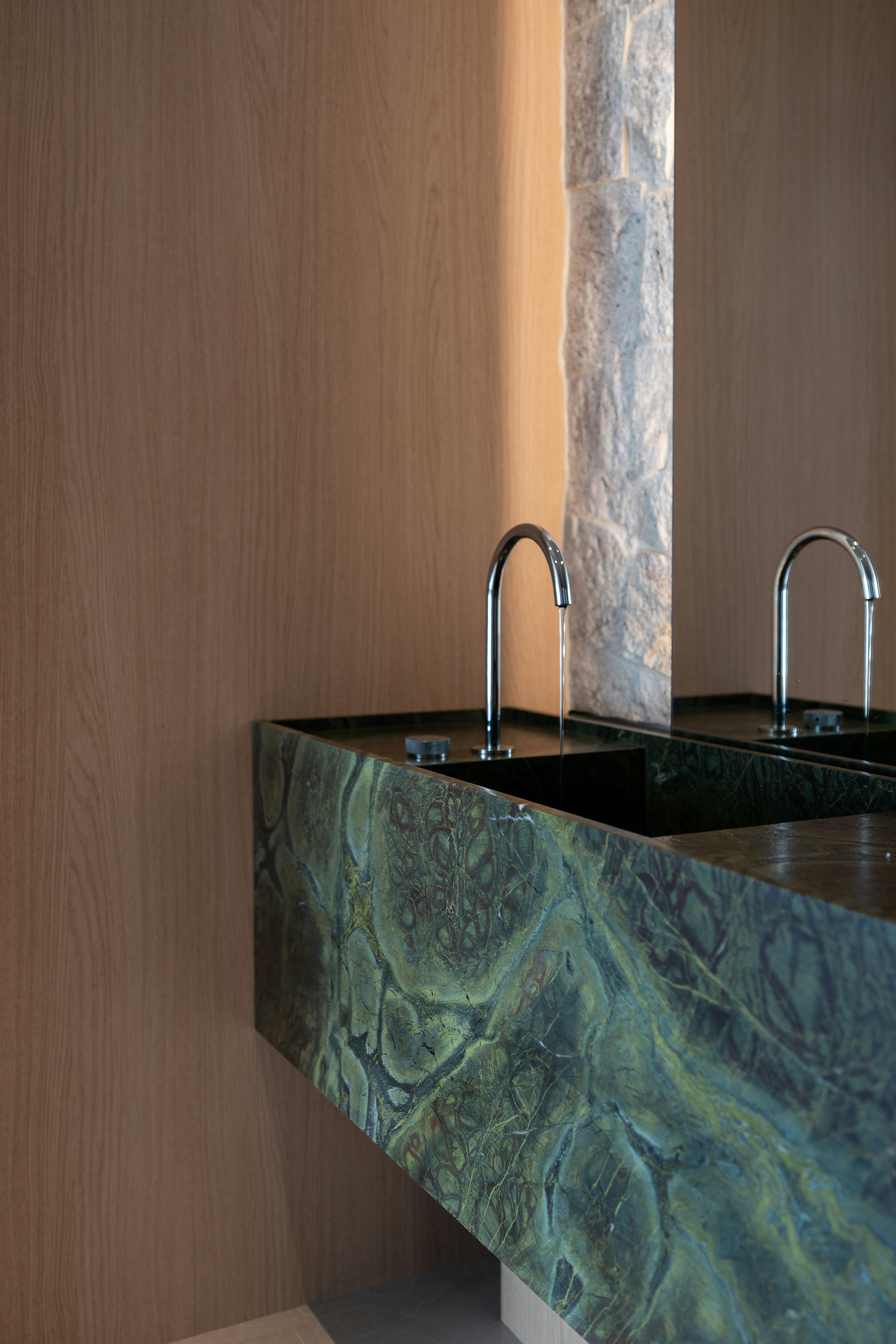 Stone-green Counter and Arched Faucets in Quiet Bath