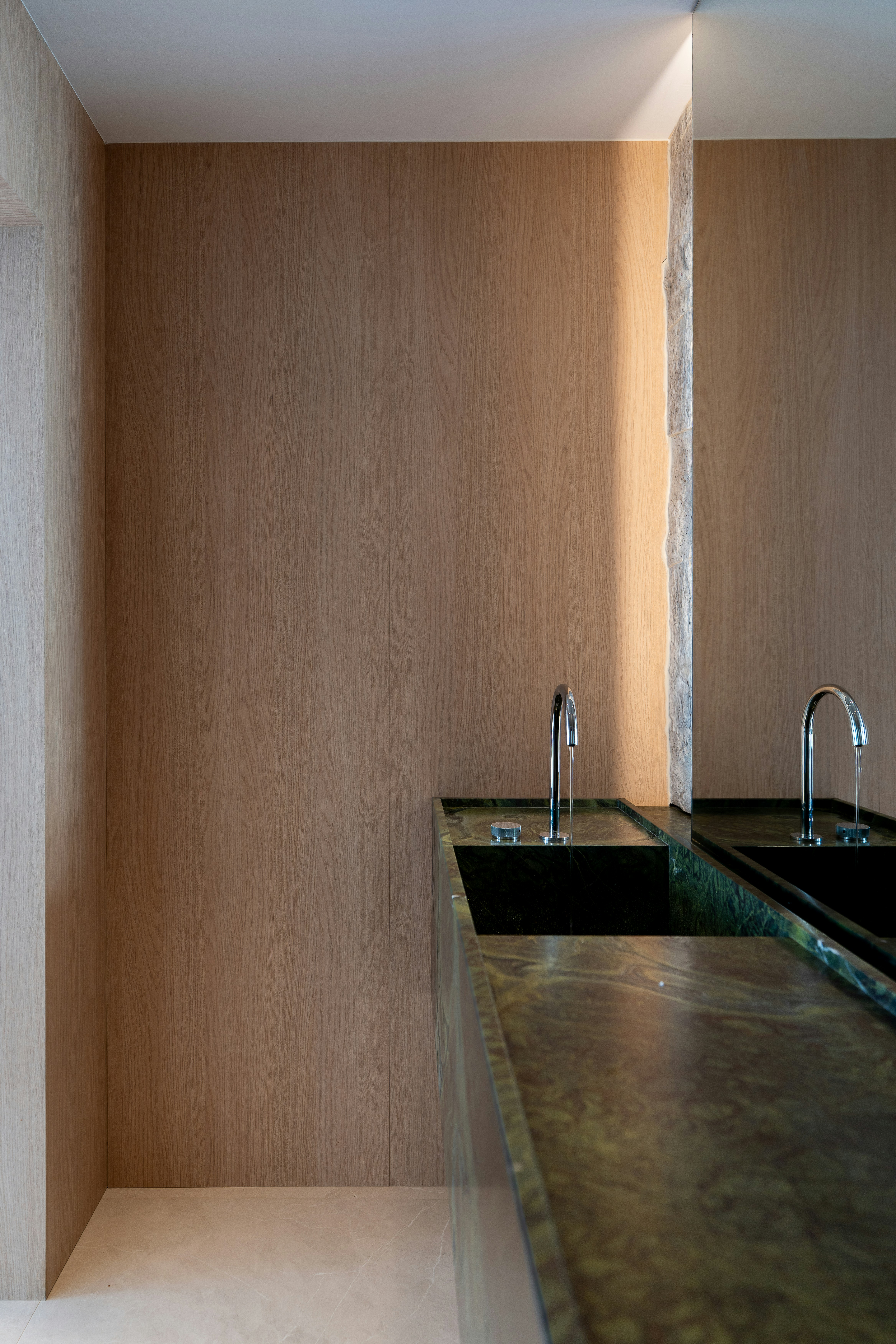 Minimalist bathroom vanity with wood paneling and stone-topped sink line