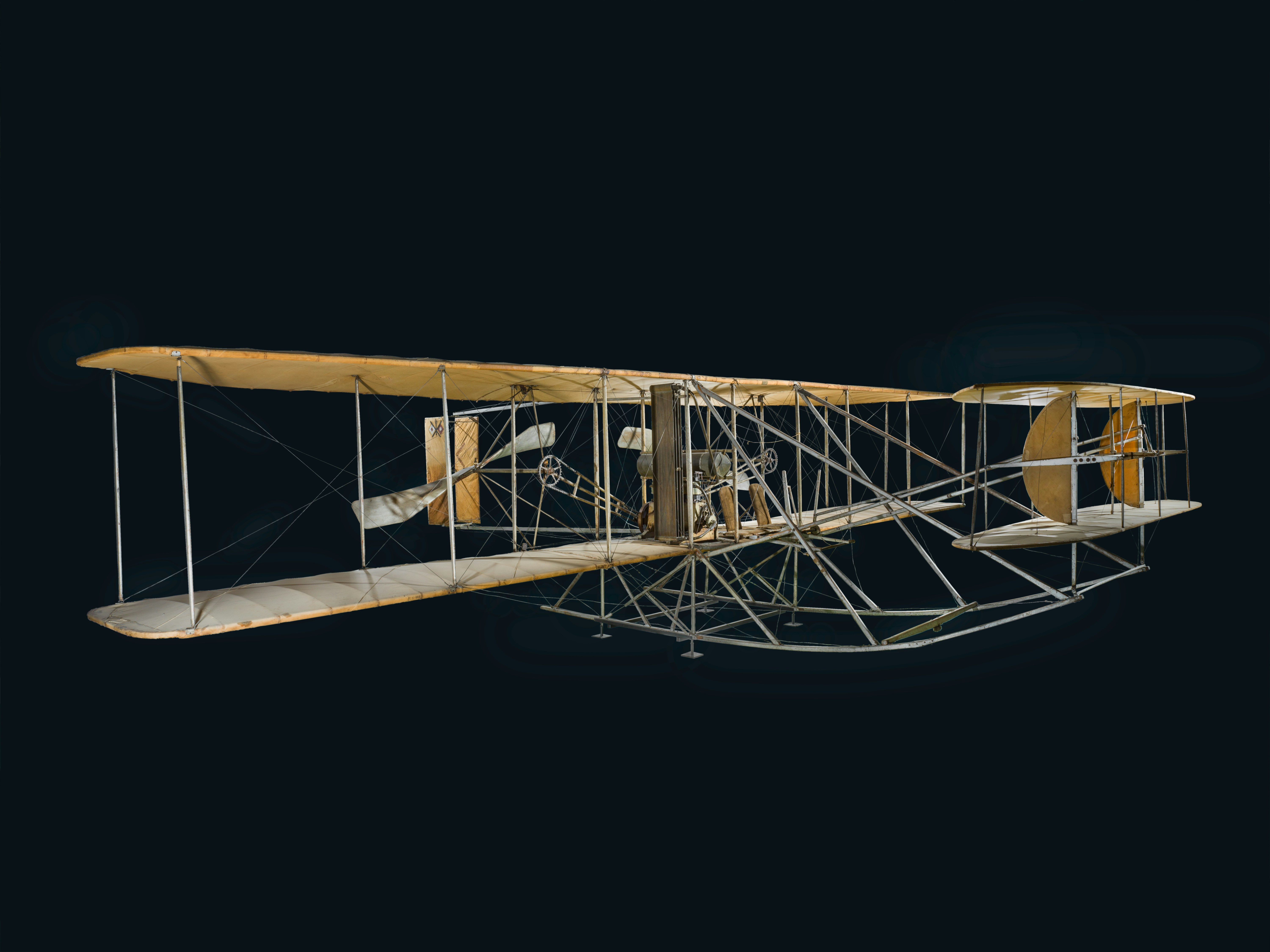 Silhouette of a historical biplane: delicate framework and fabric wings in a dark studio