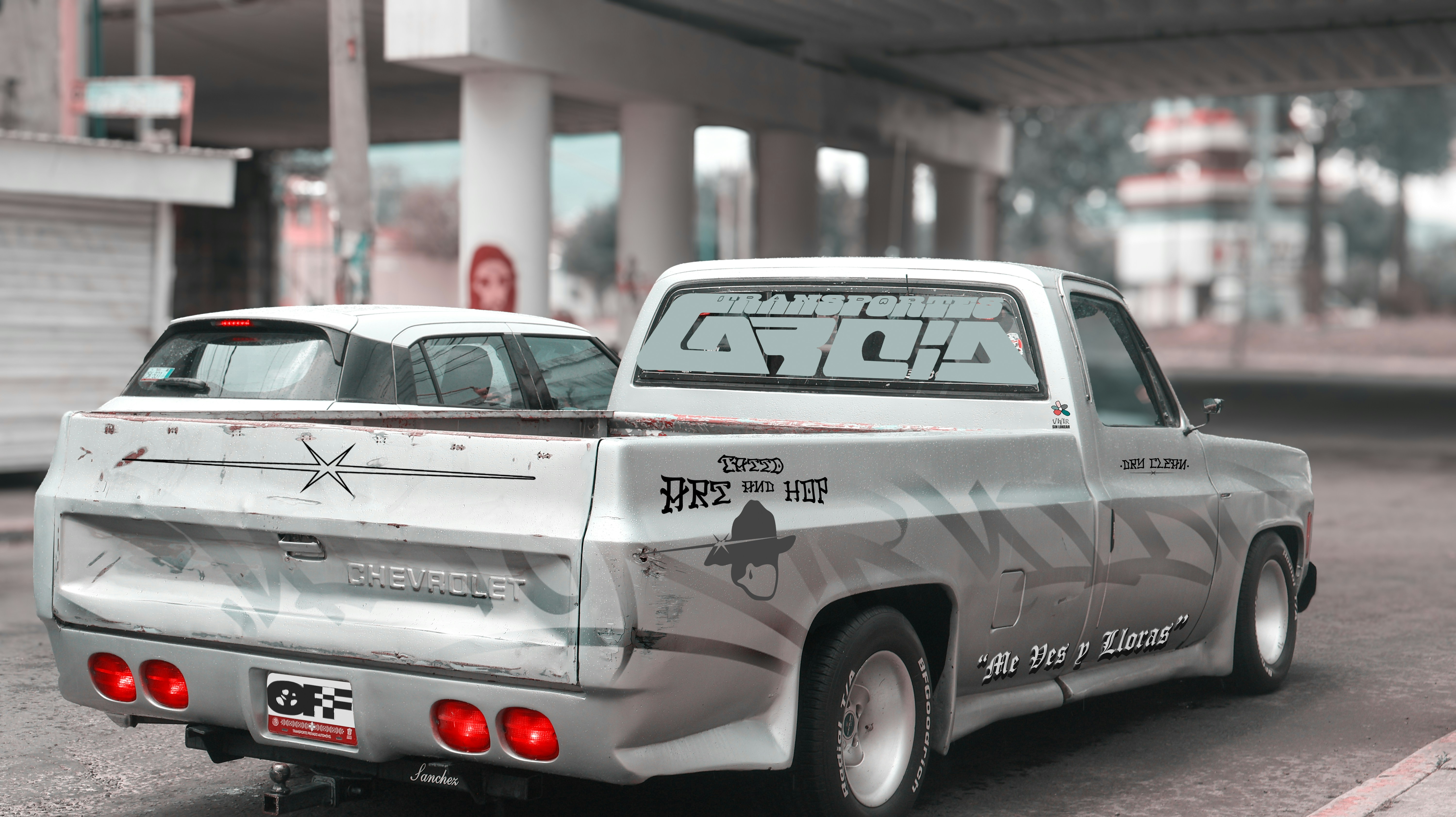 Weathered Pickup with Custom Graphics under Neon-tinged Overpass