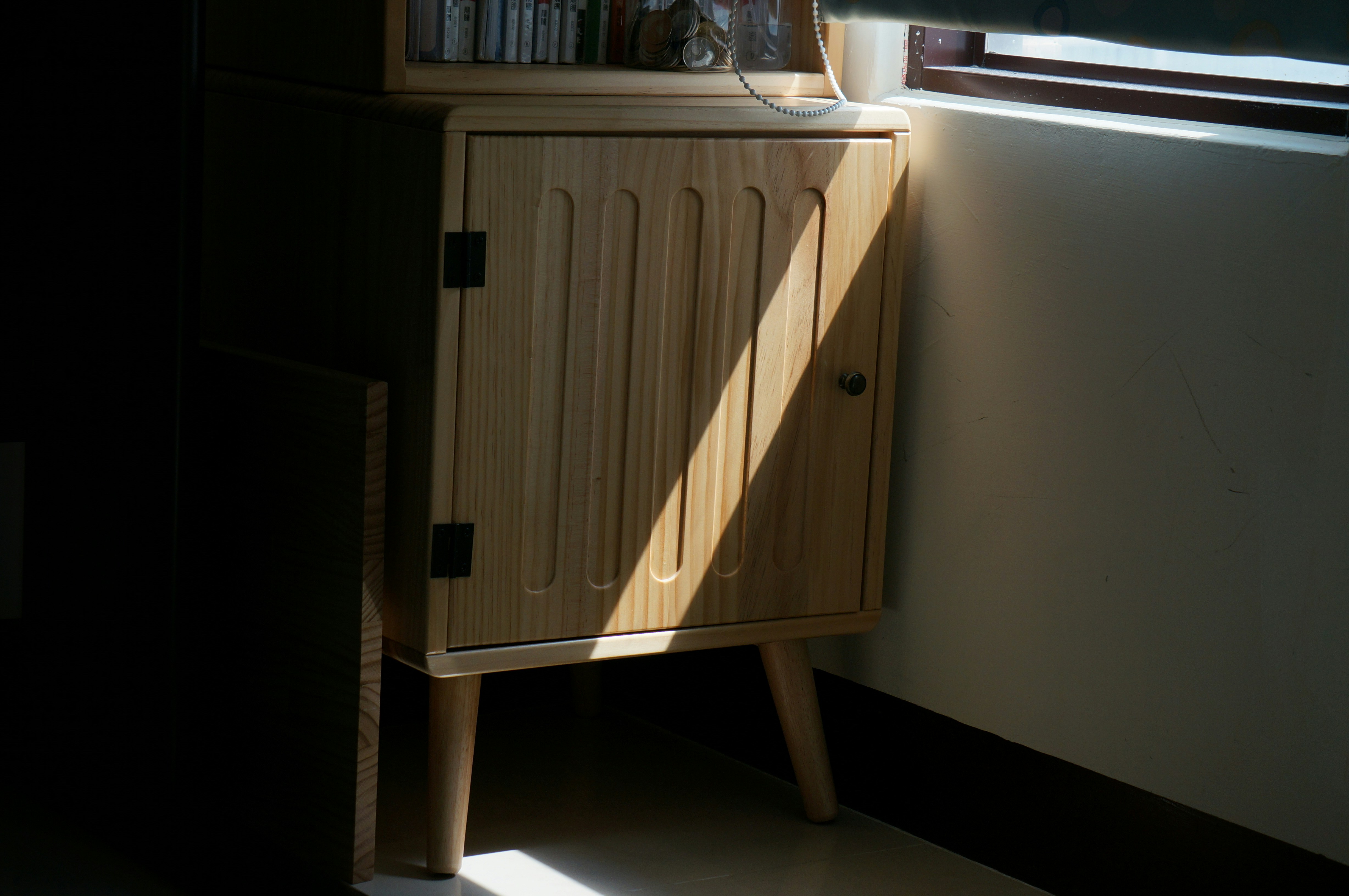 Sunlit cabinet corner: mid-century wood under a beam of daylight