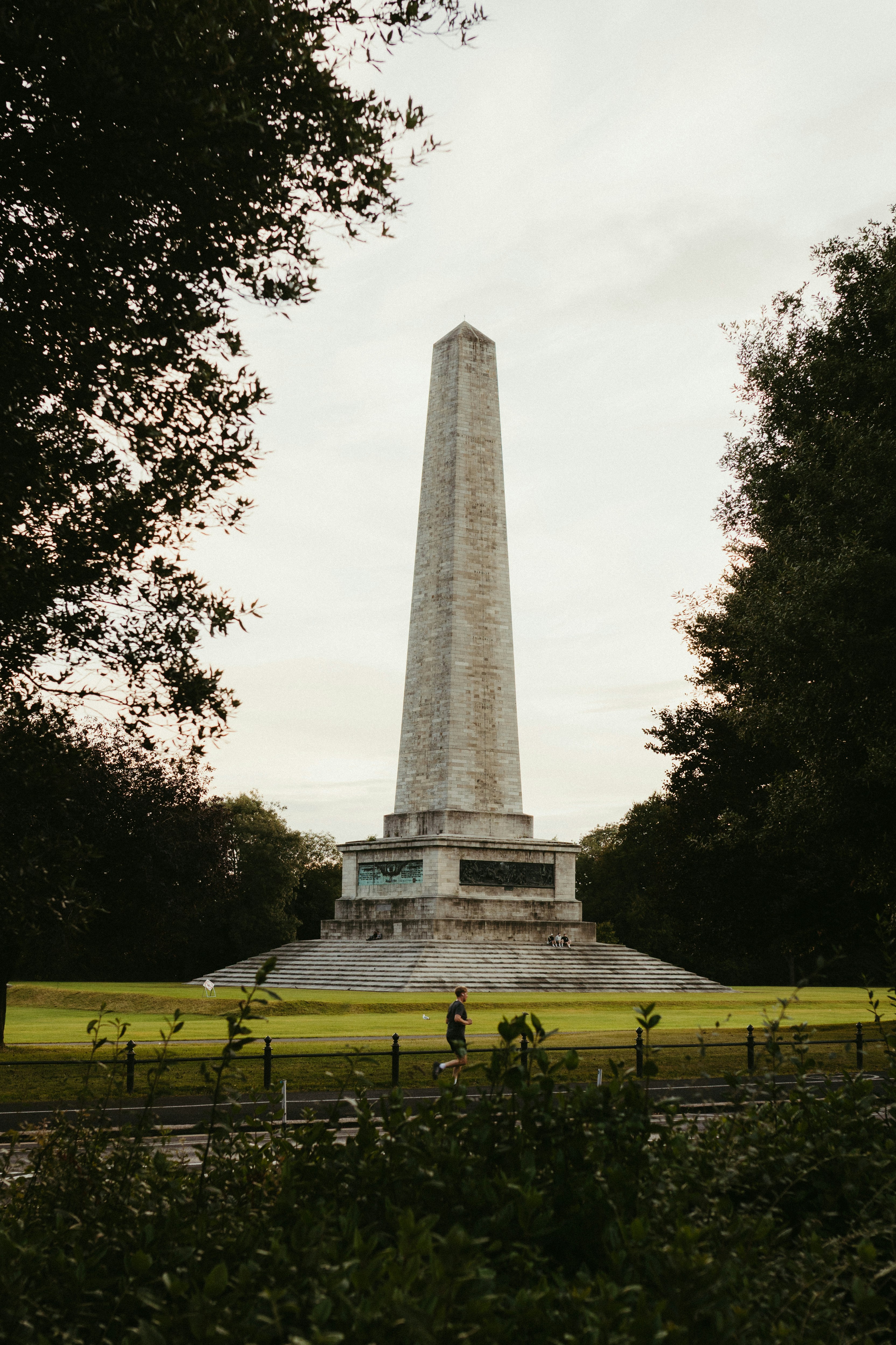 Monumental Obelisk Framed by Trees with a Runner in the Foreground