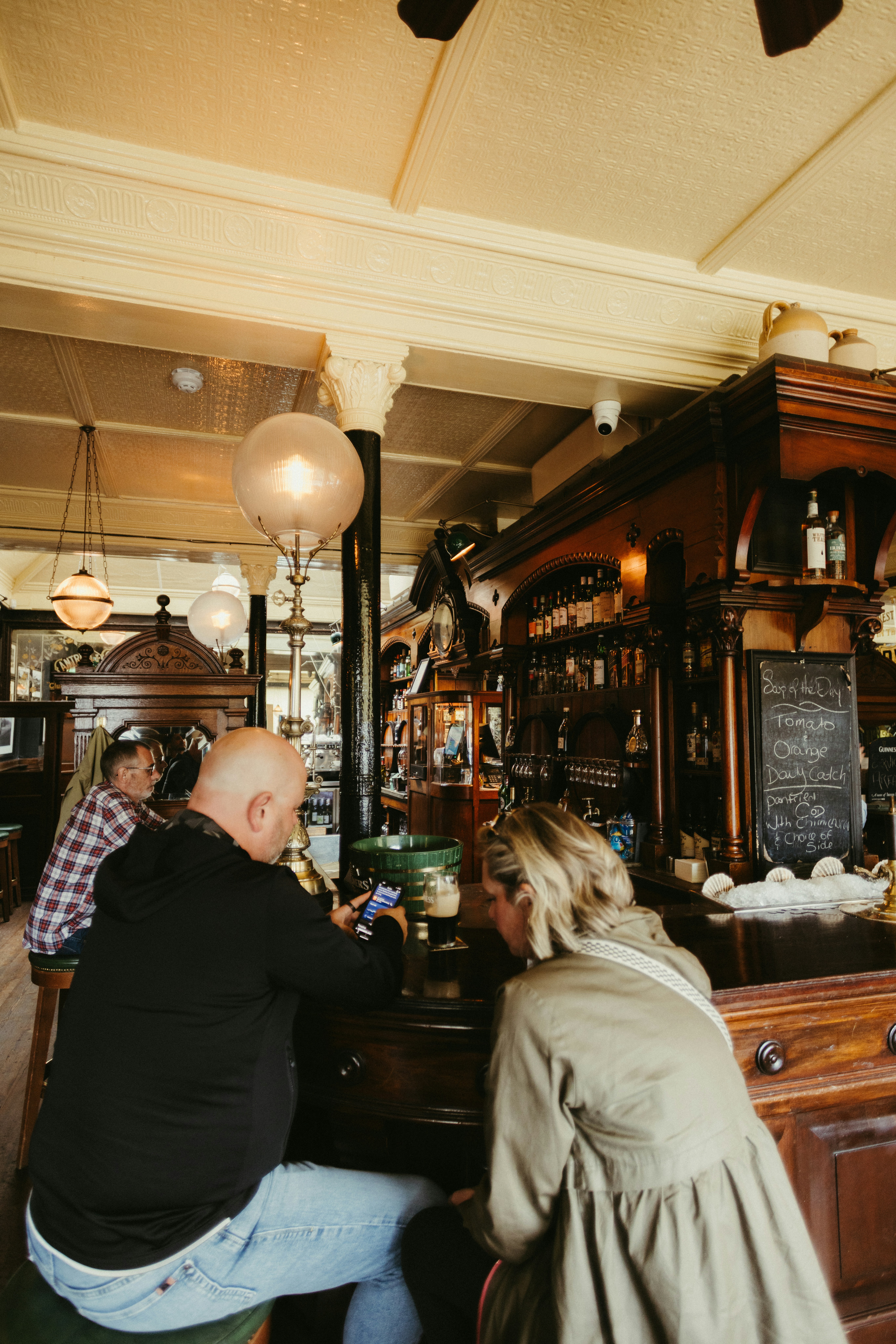 Warm Barroom Moments: Two patrons at the wooden counter in a bustling pub